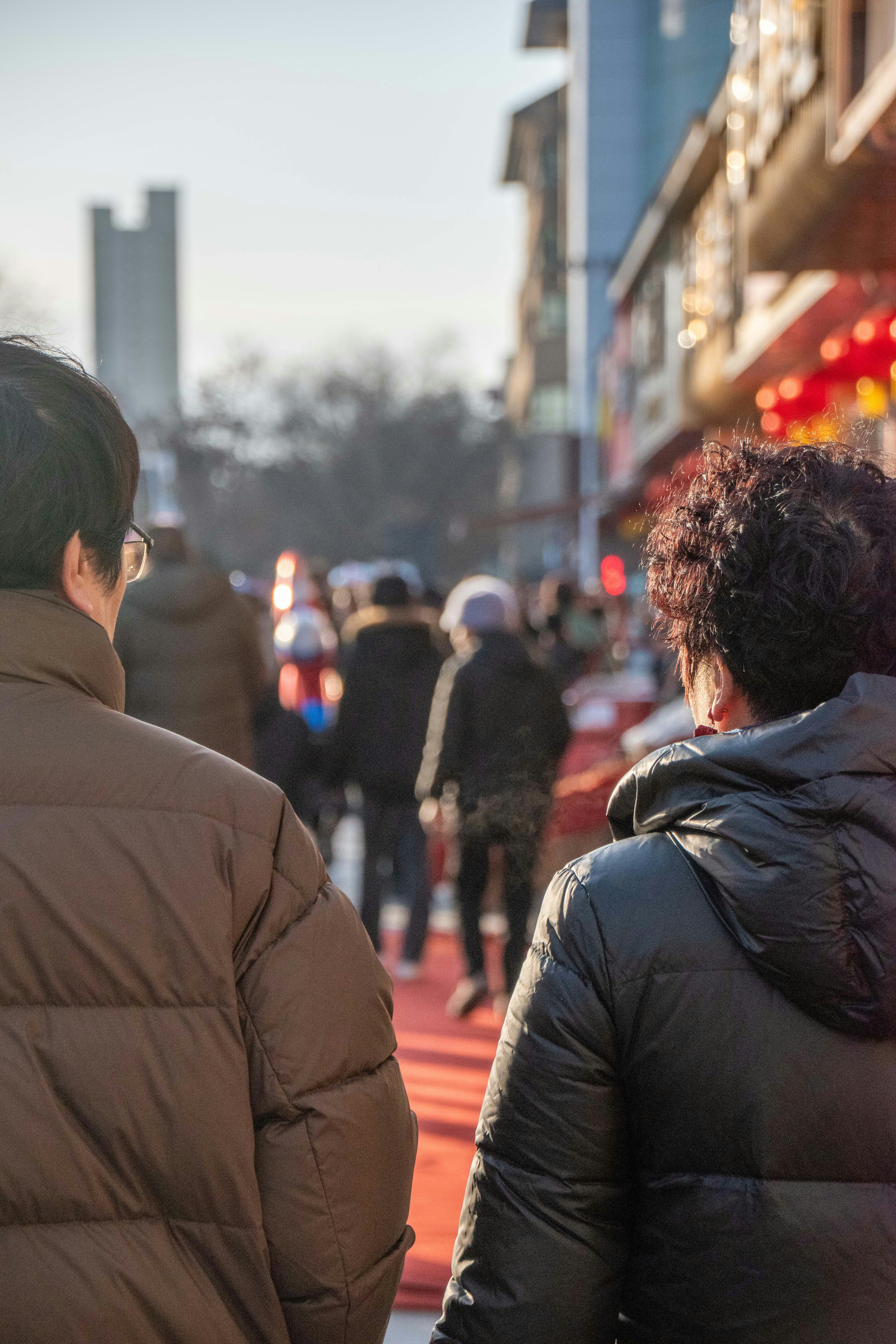 Two Warm Jackets in a Bustling Street: A City Portrait at Dusk