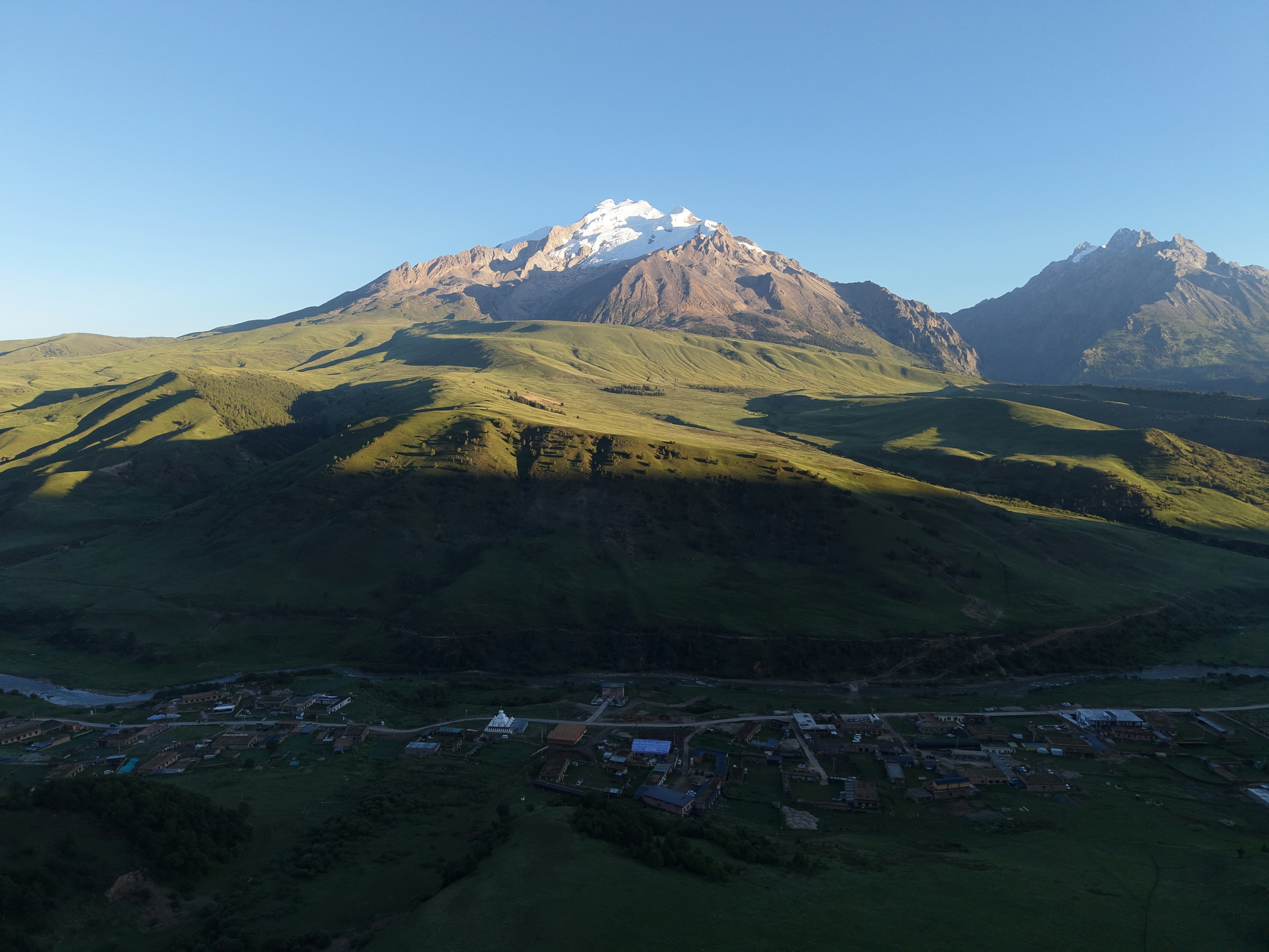 Snow-capped peaks over sunlit valley and village