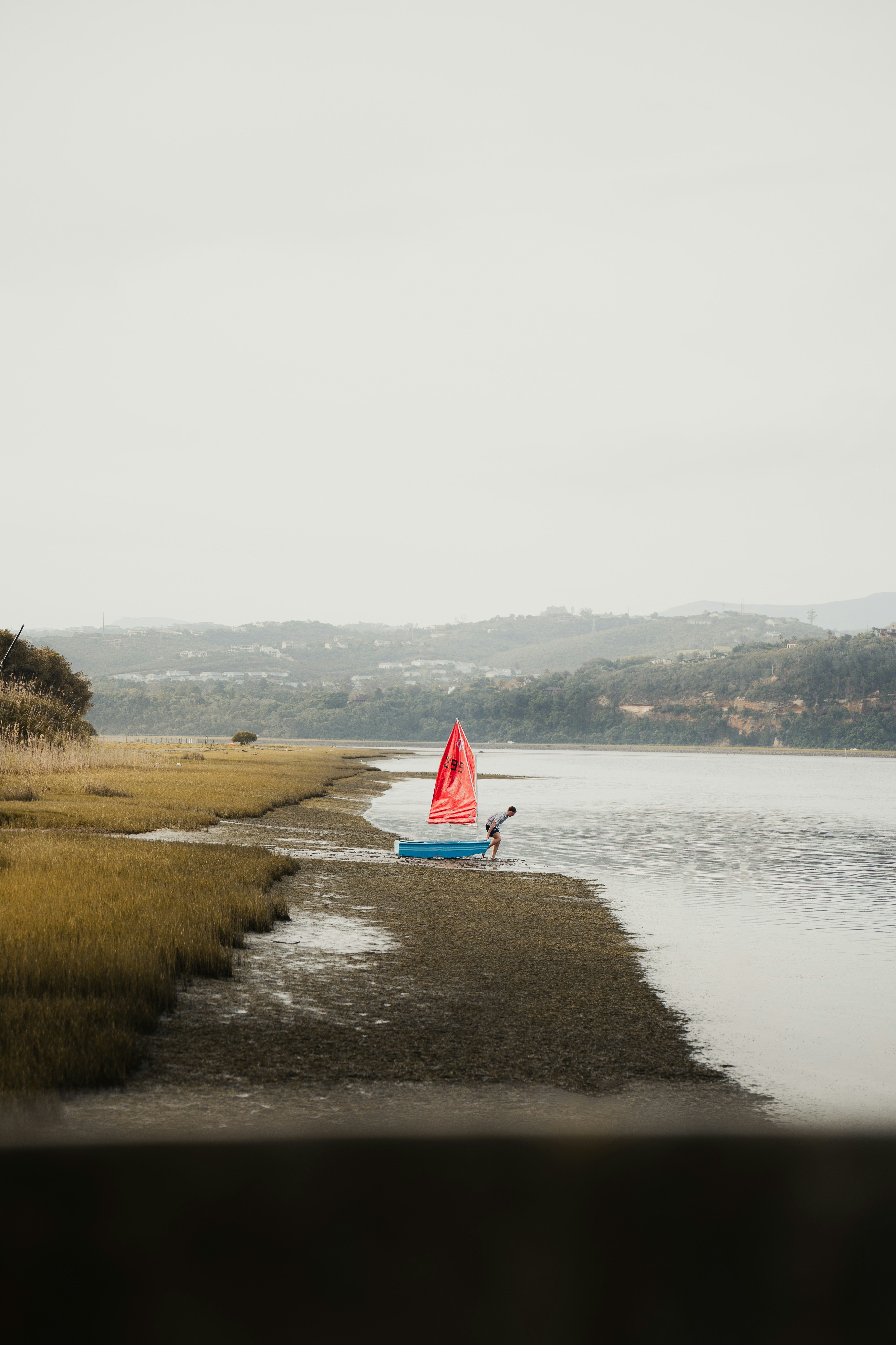 Red Sail, Blue Boat: A Quiet Horizon by the Shore