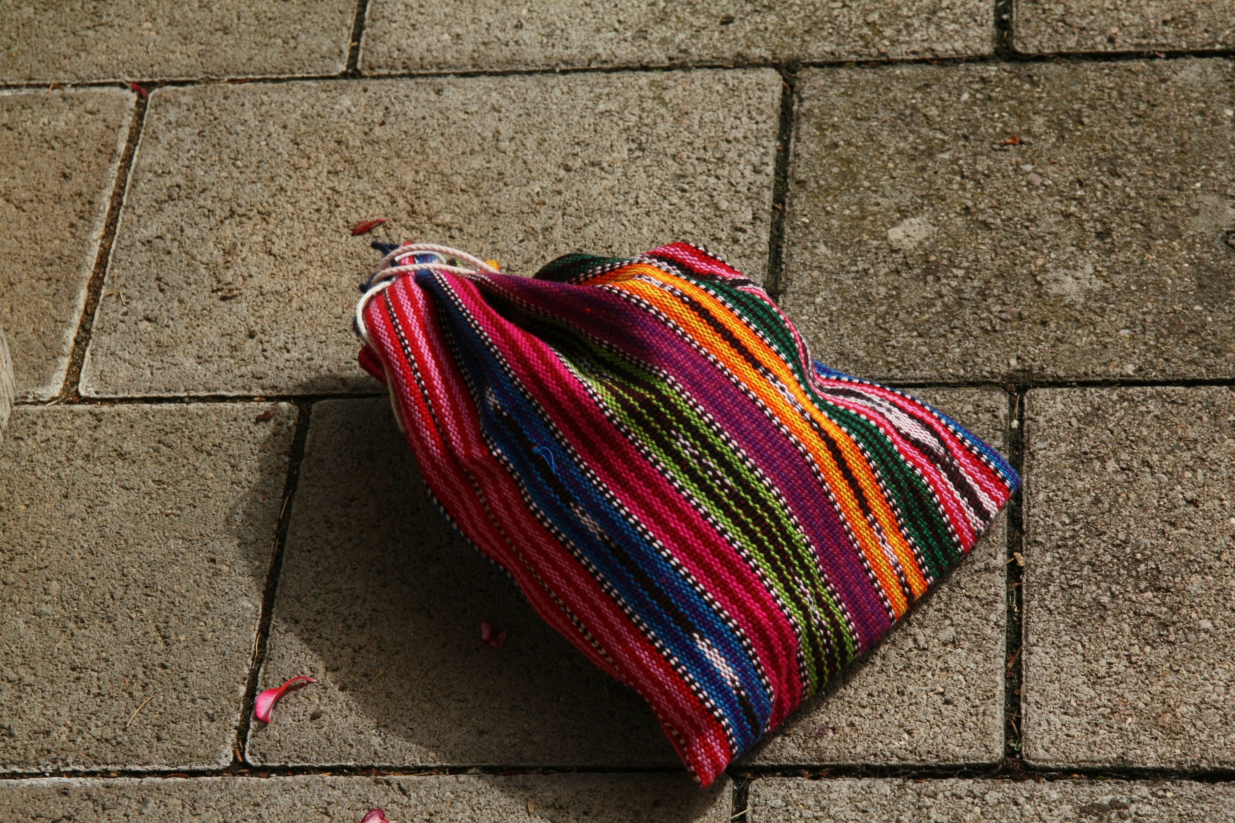 Stripes on the Walk: a Colorful Fabric Bag Resting on Patio Tiles