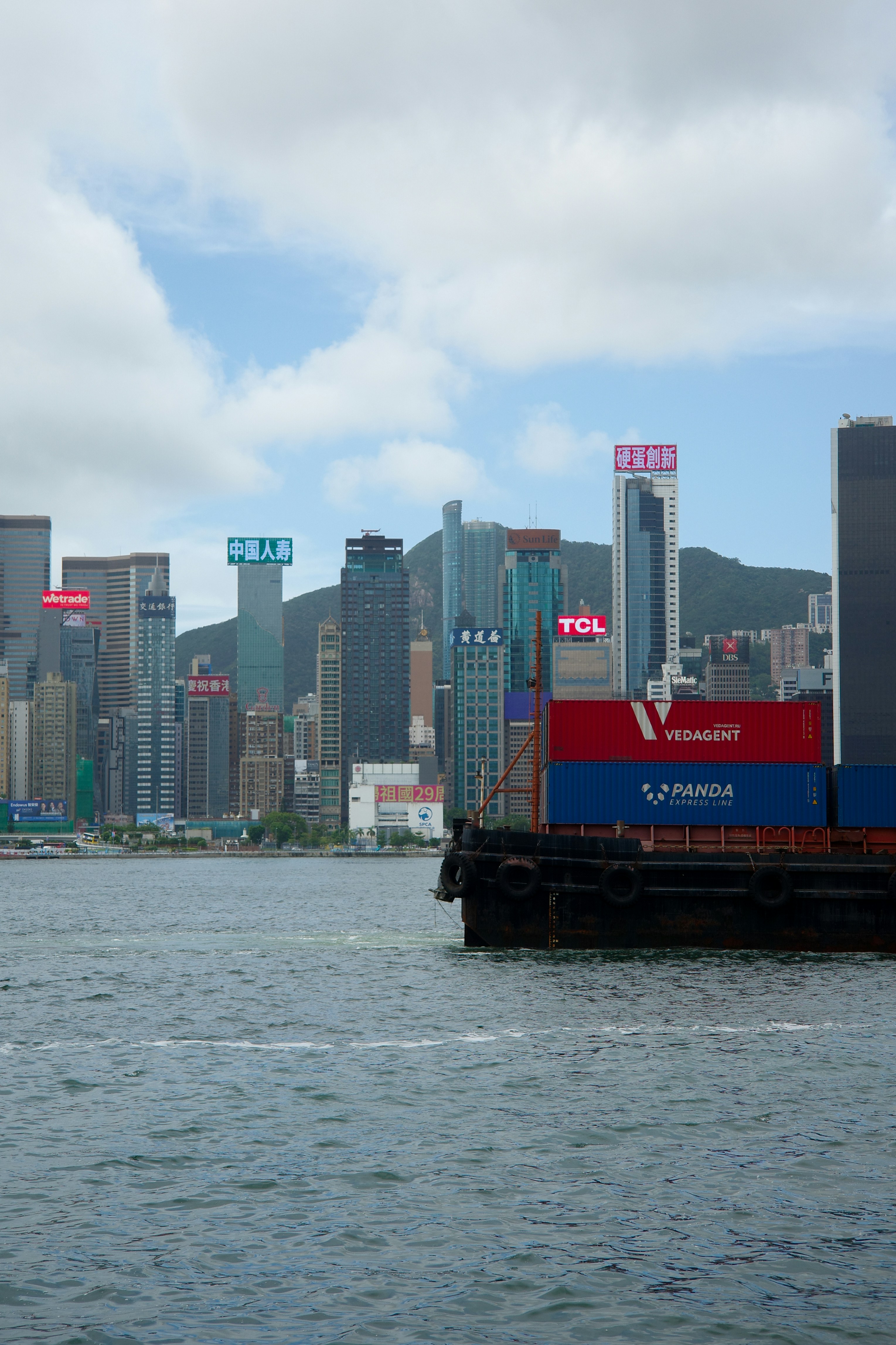  cargo ship at harbor with city skyline and stacked containers