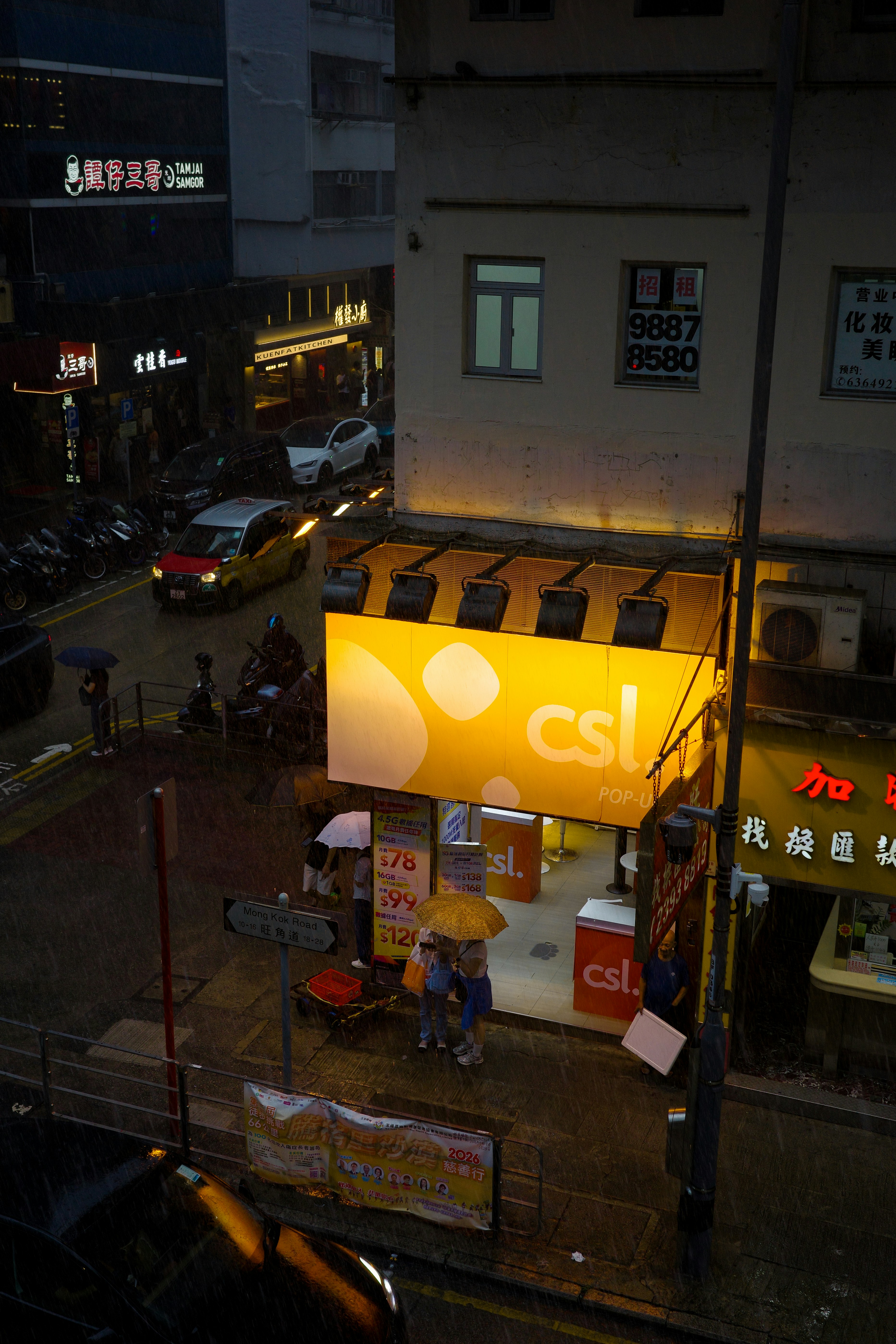 Yellow storefront glow in rainy street evening