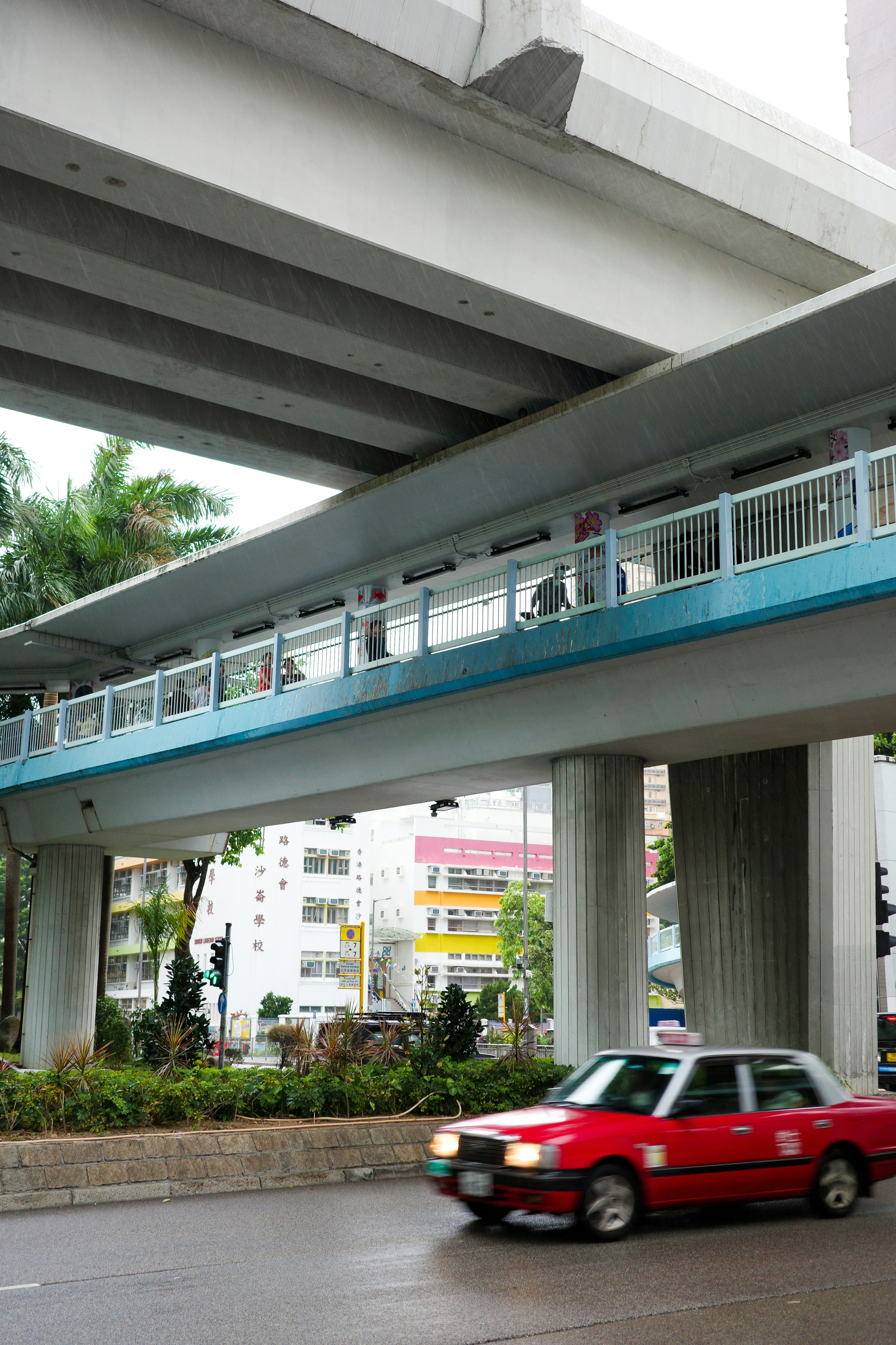 Underpass Transit: A Moving Red Taxi Beneath Angular Bridges