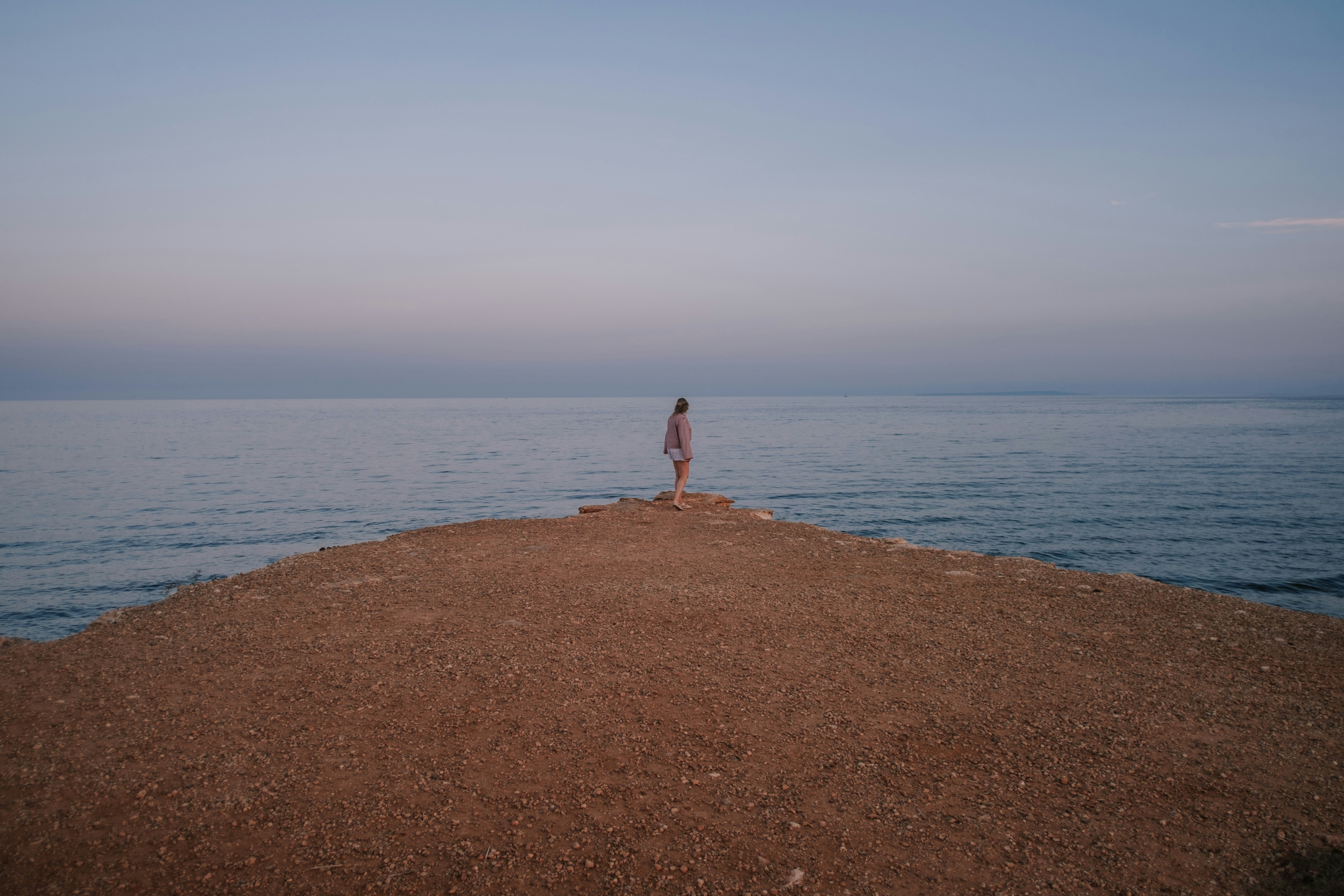 Edge of Calm: A lone wanderer at the water’s horizon