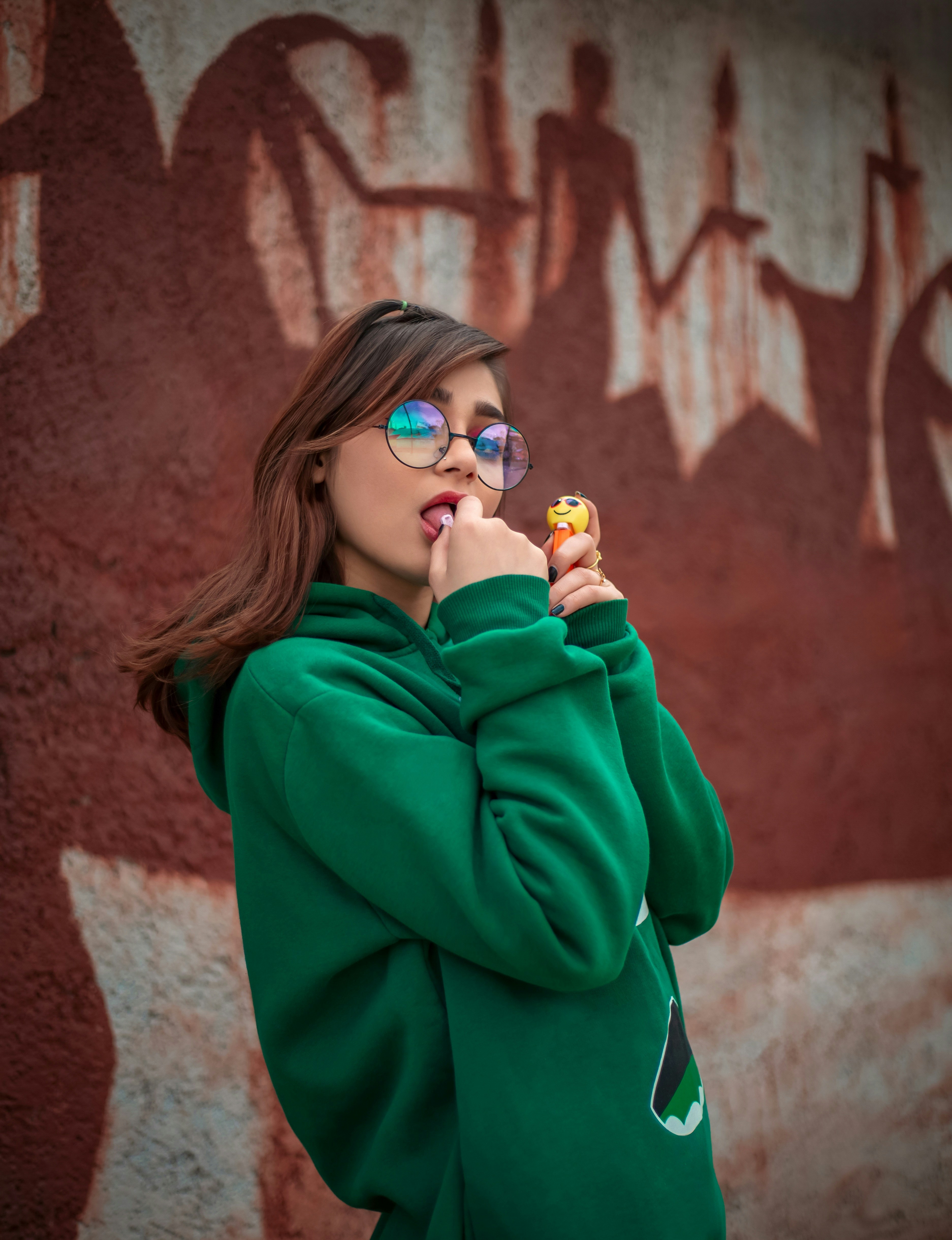 Green Hoodie, Neon Glasses, and a Painted Wall: A Quiet Moment in Color