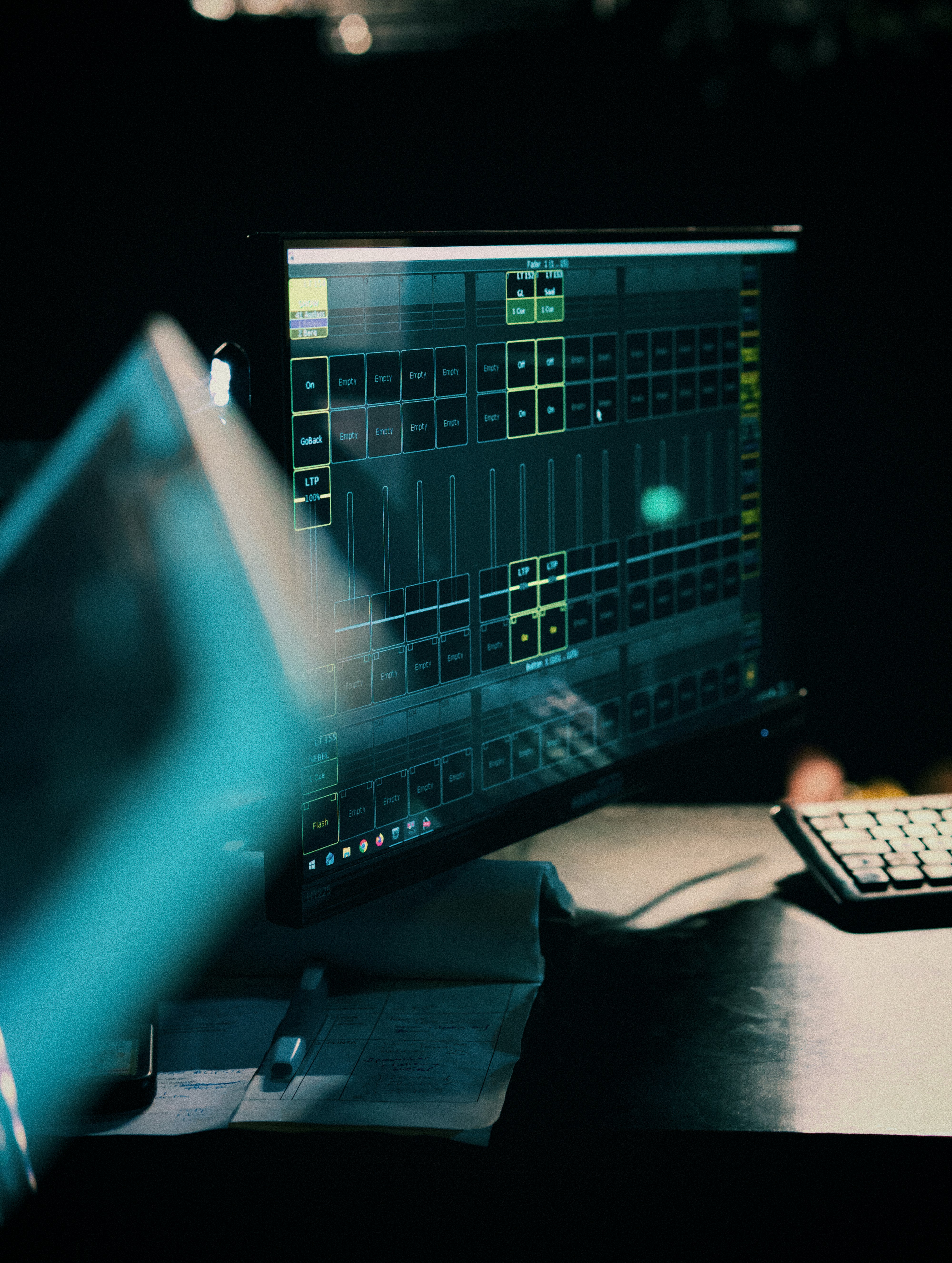 High-contrast monitor displaying a digital control interface sits on a dim desk with a keyboard nearby.