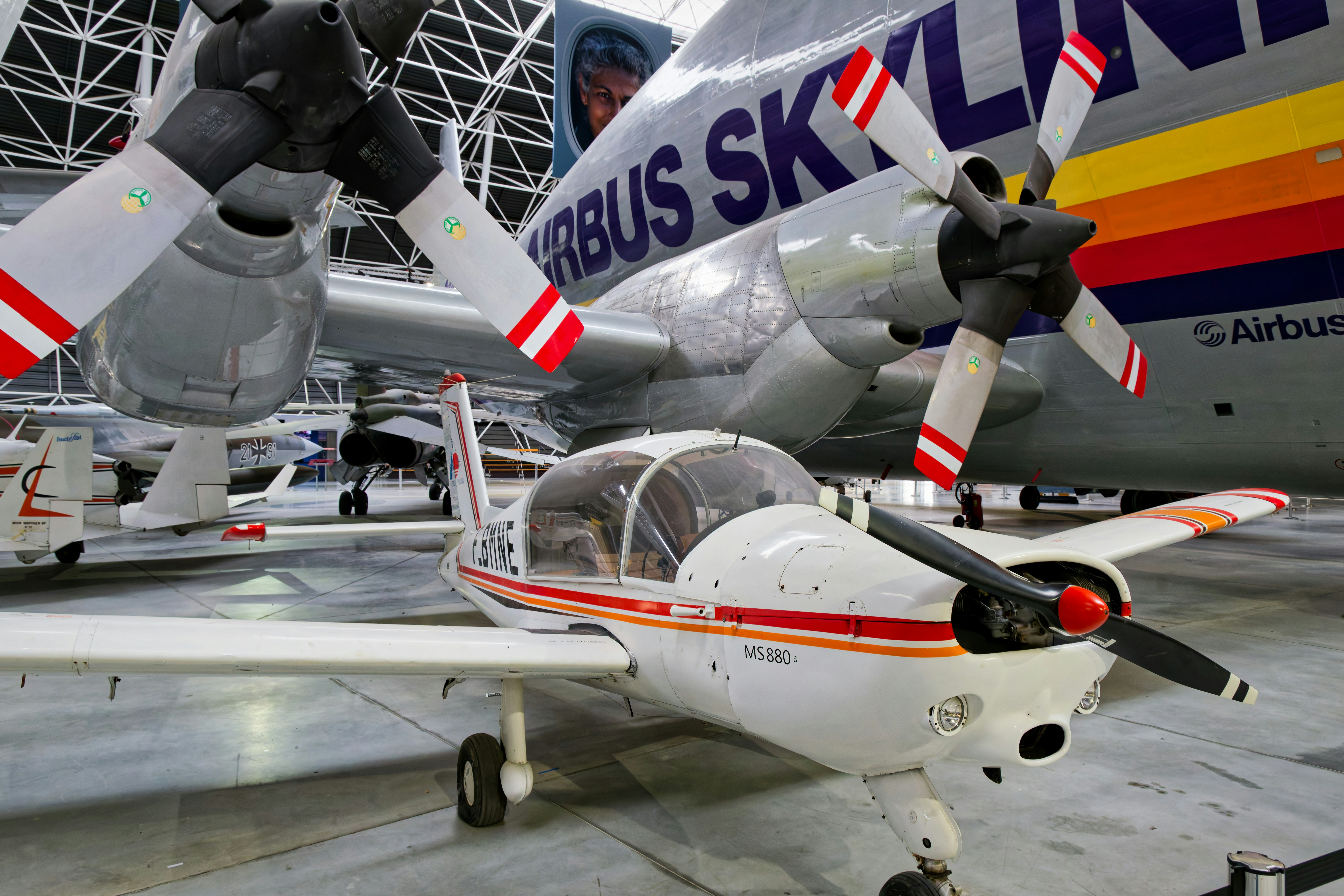 Small White Jet Scout at the Wing of a Large Multiengine Aircraft
