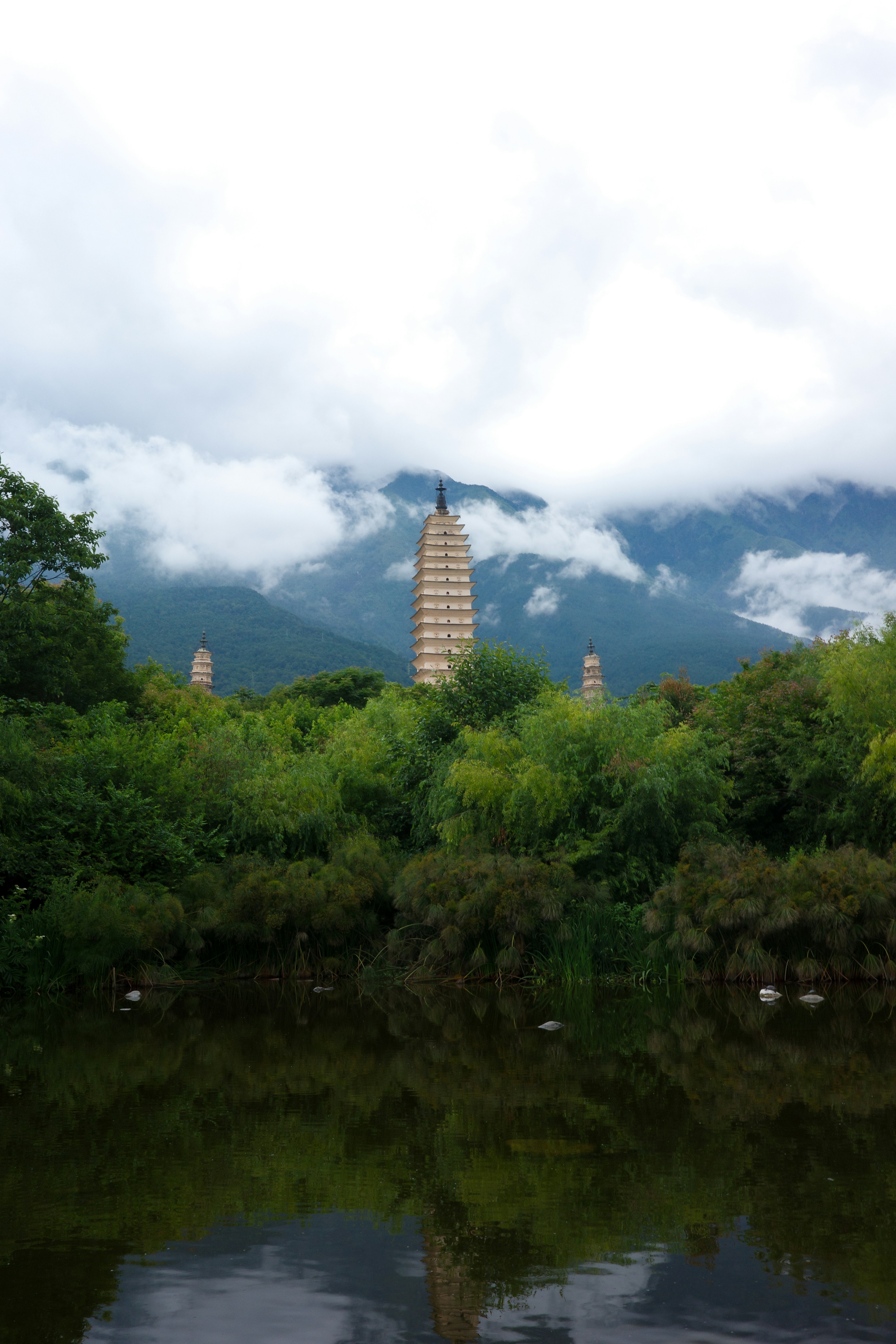 Pagoda Rising Above Green Canopy, Lake Reflections in Foreground