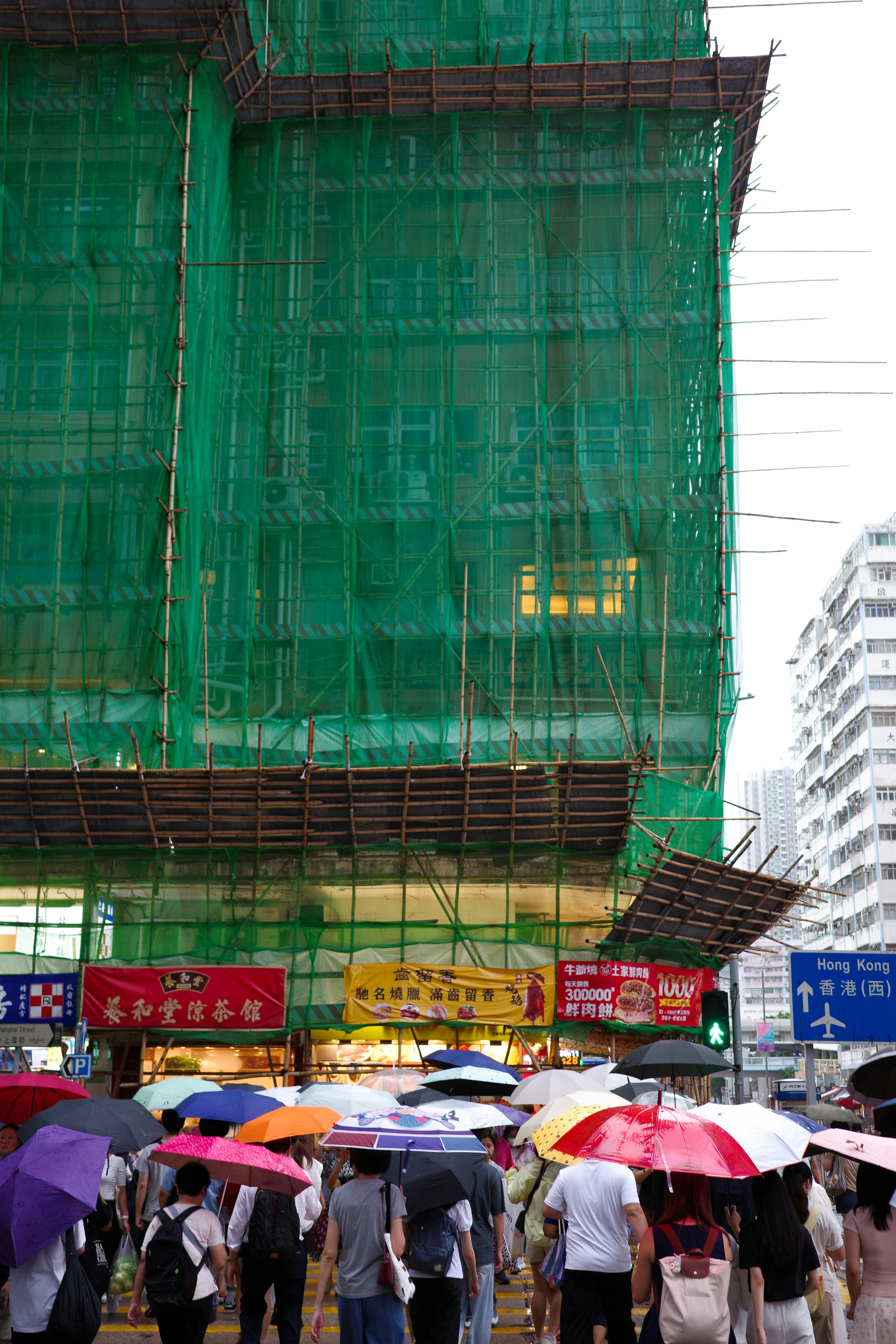Under Green Veil: City Crowd at a Construction Site