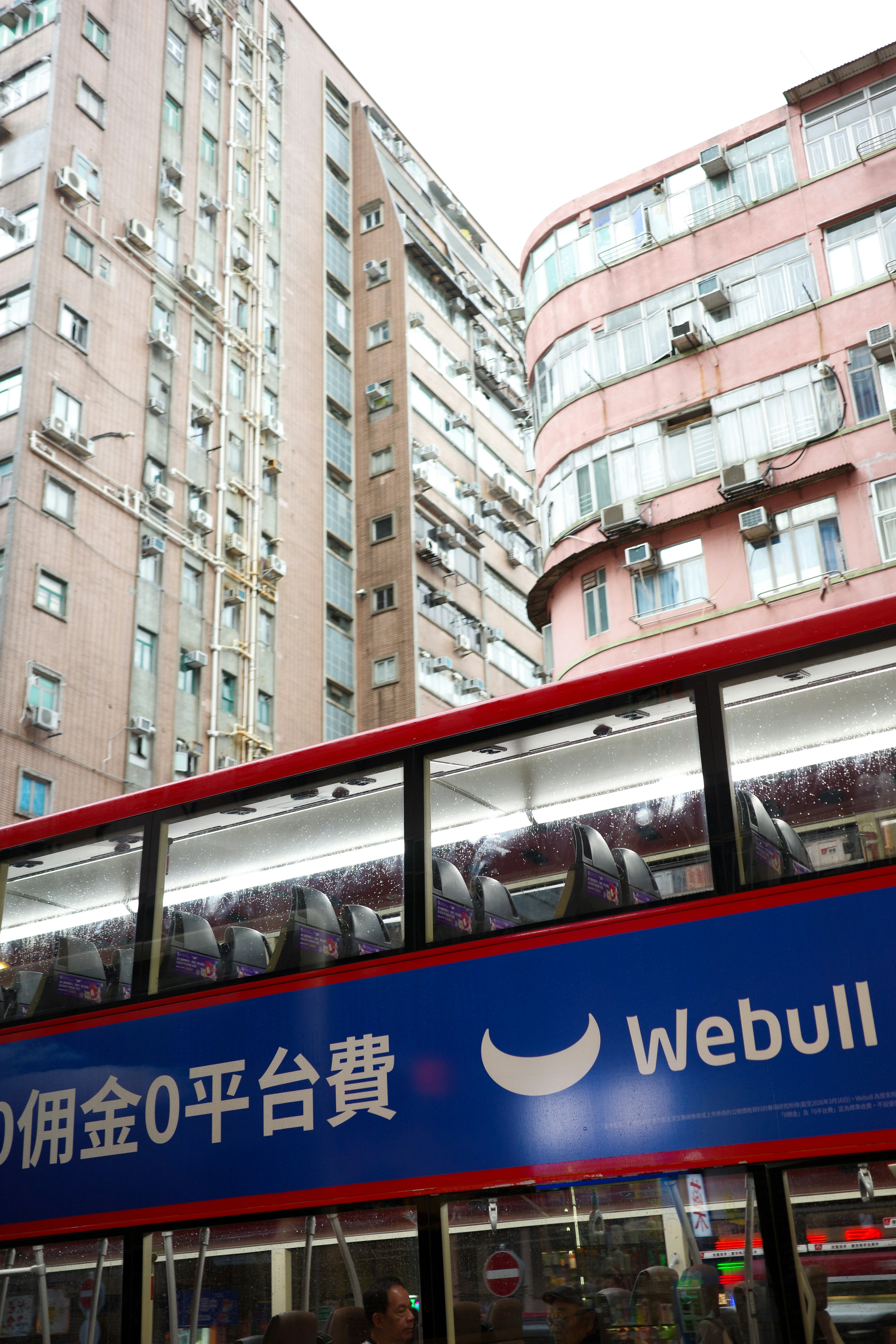 Urban Bridge of Signage: Red Bus in a City Canyon