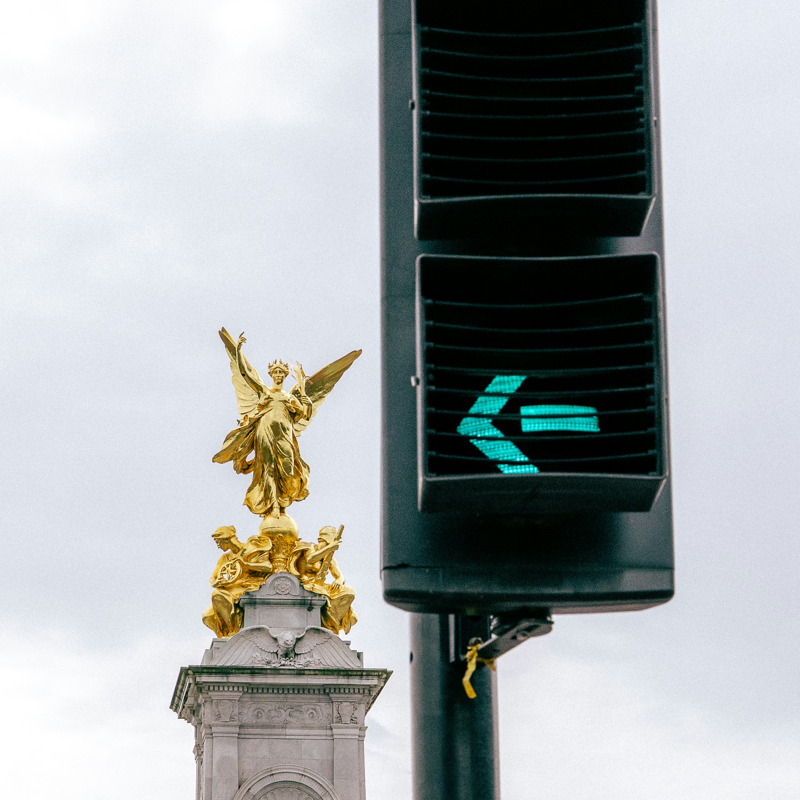 Golden Angel on a Marble Pedestal: A City Monument Under Soft Skies