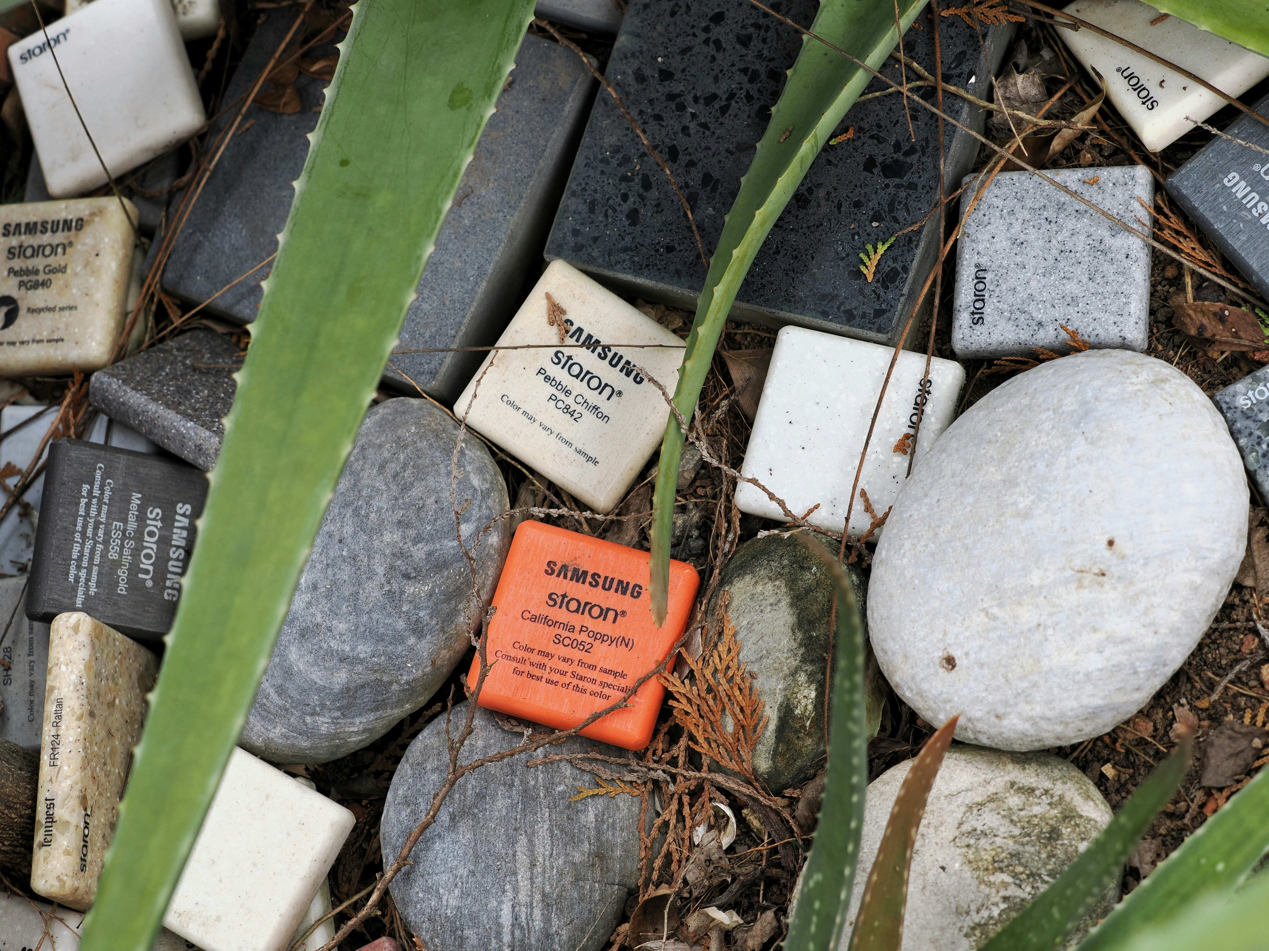 Disused Samsung 'Staron' fragments among river rocks