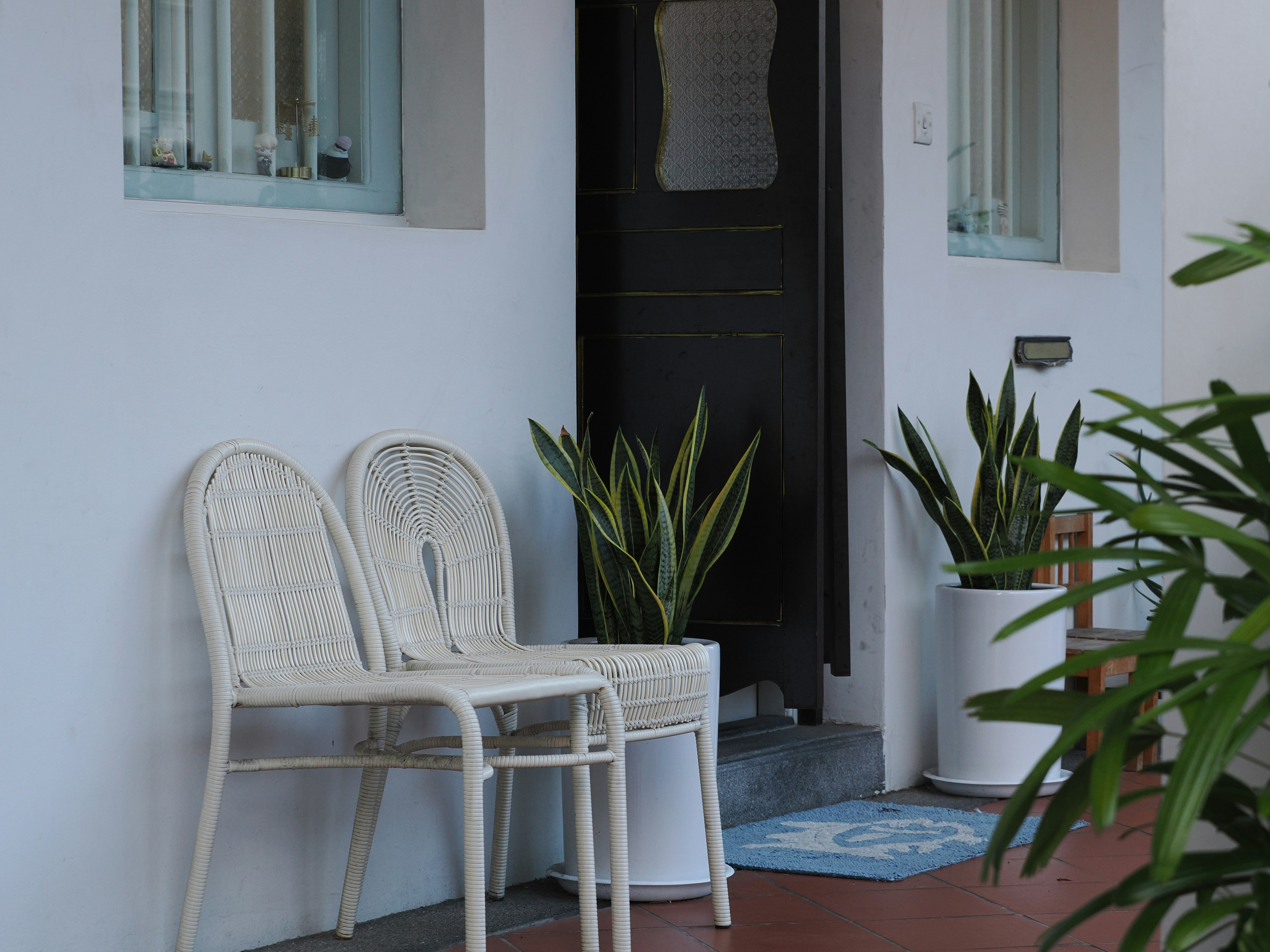 Quiet doorstep with two white chairs under a blue mat