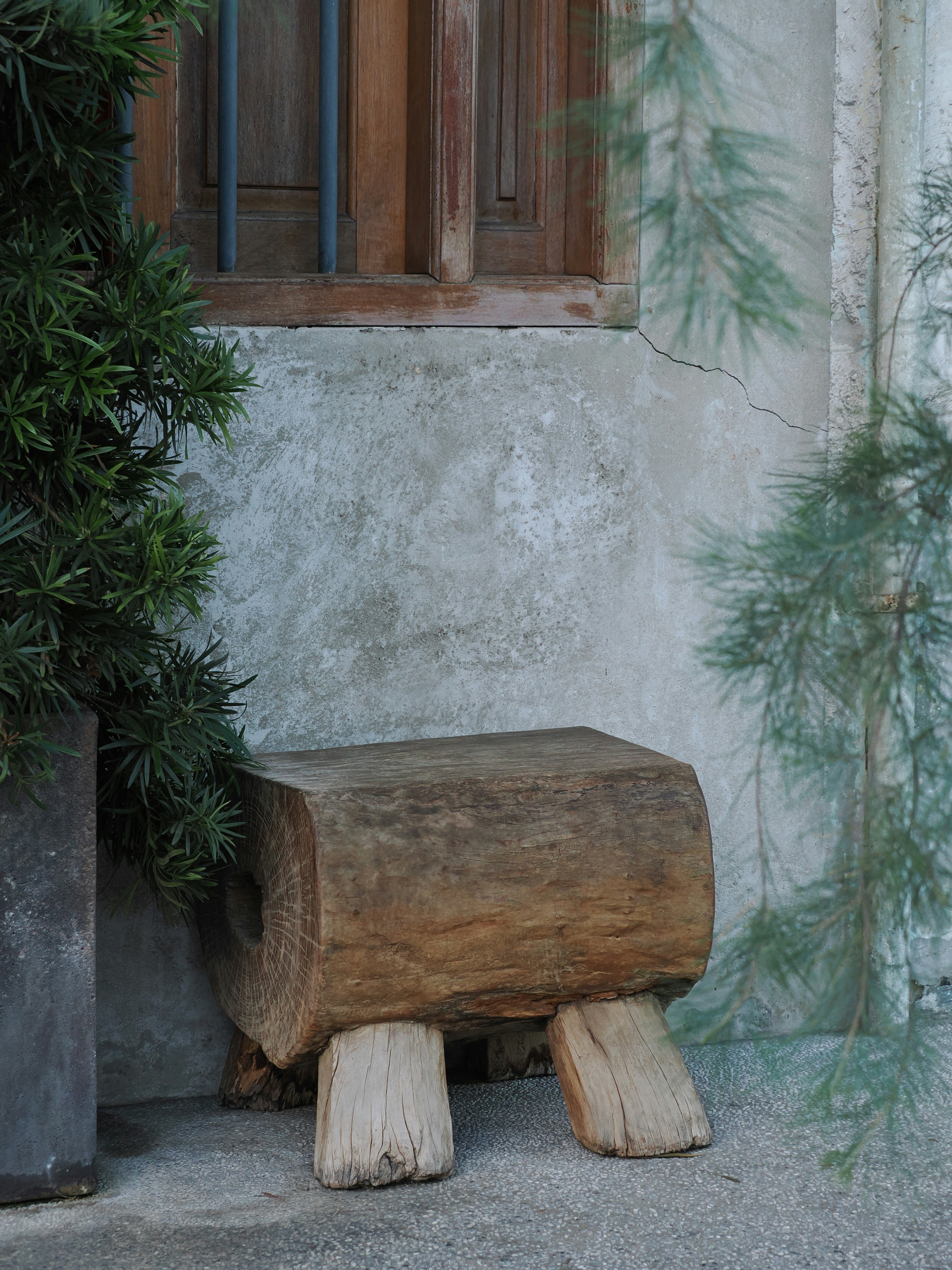Weathered Log Stool by a Stone Wall