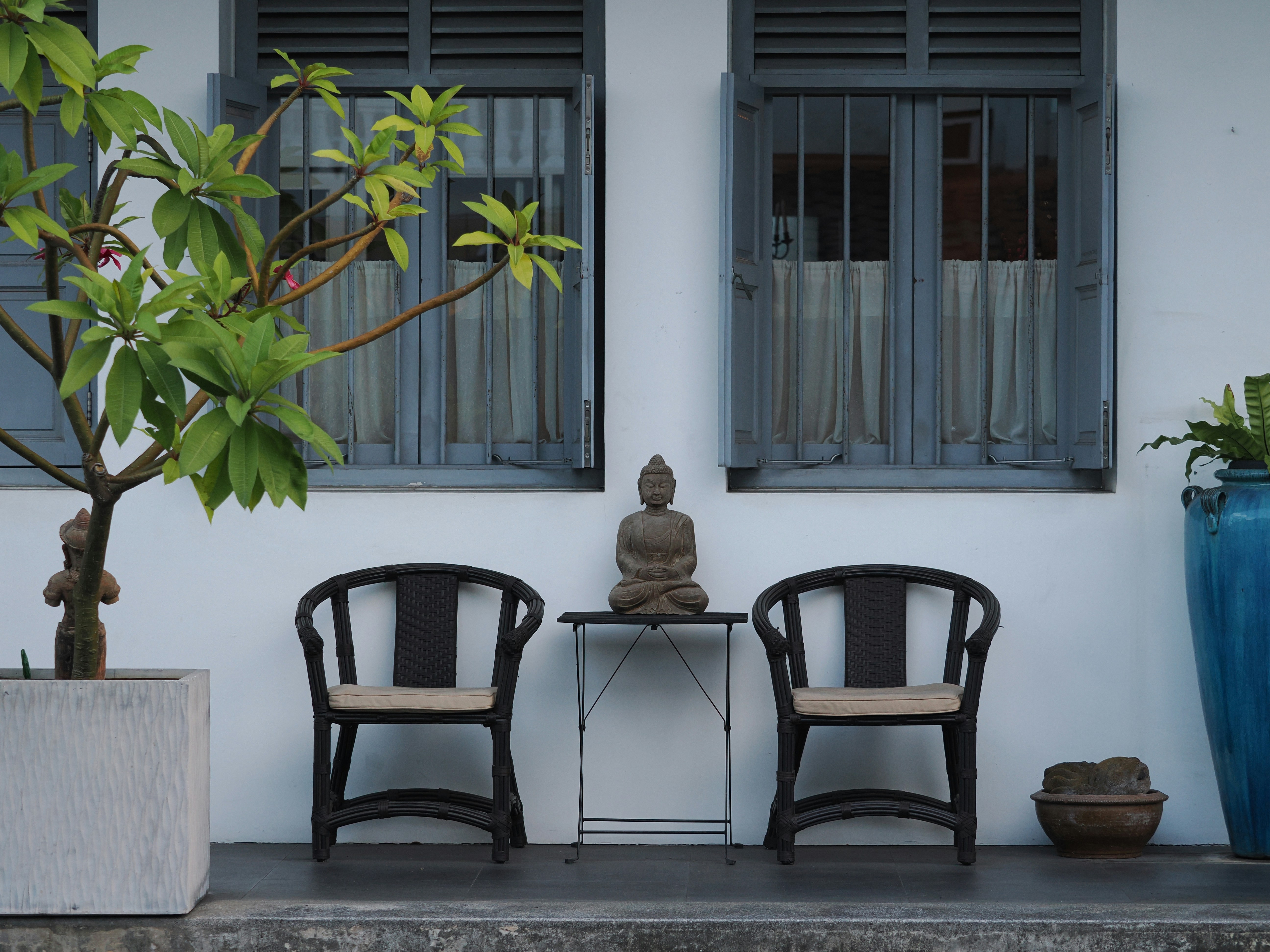 Tranquil Courtyard Dialogue: Buddha, Chairs, and a Quiet Vase