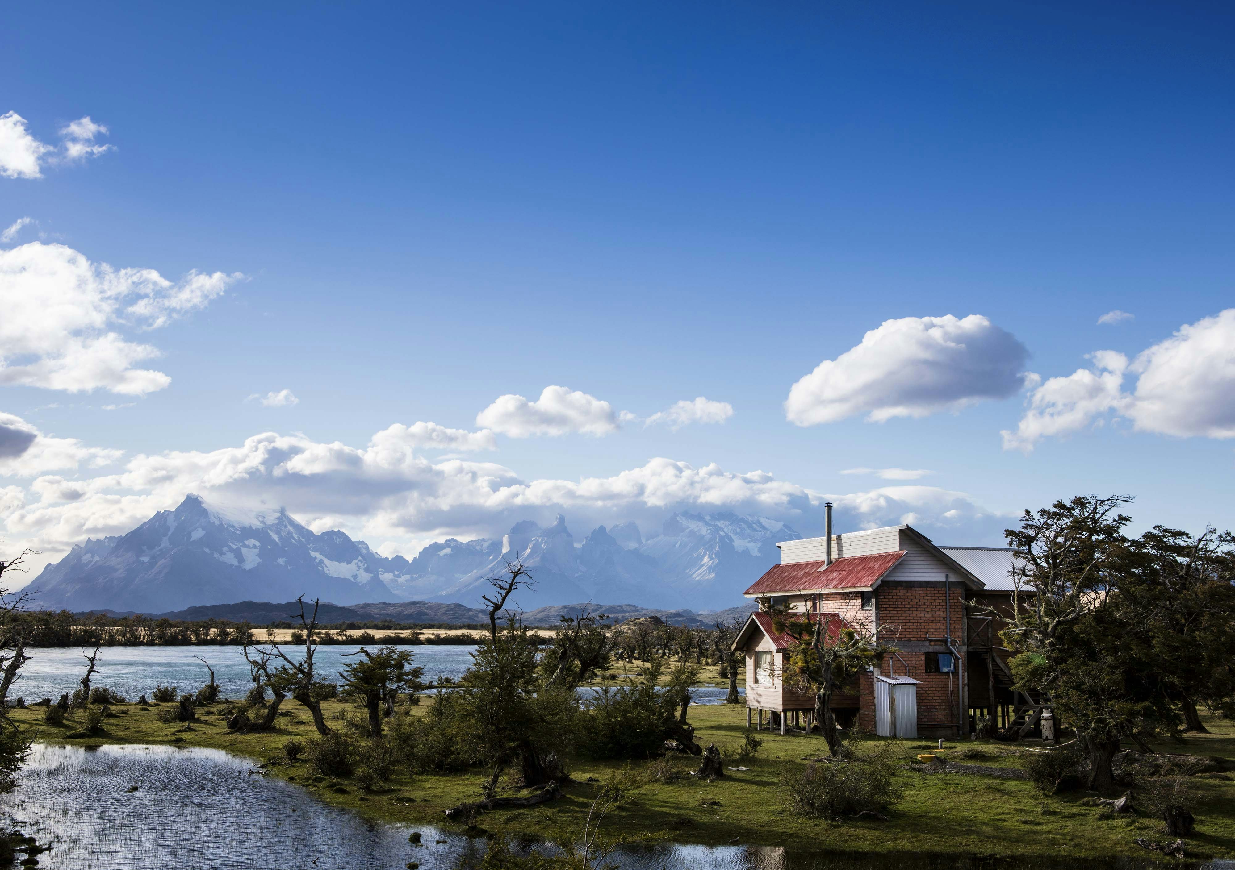 Rustic House by a Quiet Lake with Snowy Peaks in the Distance