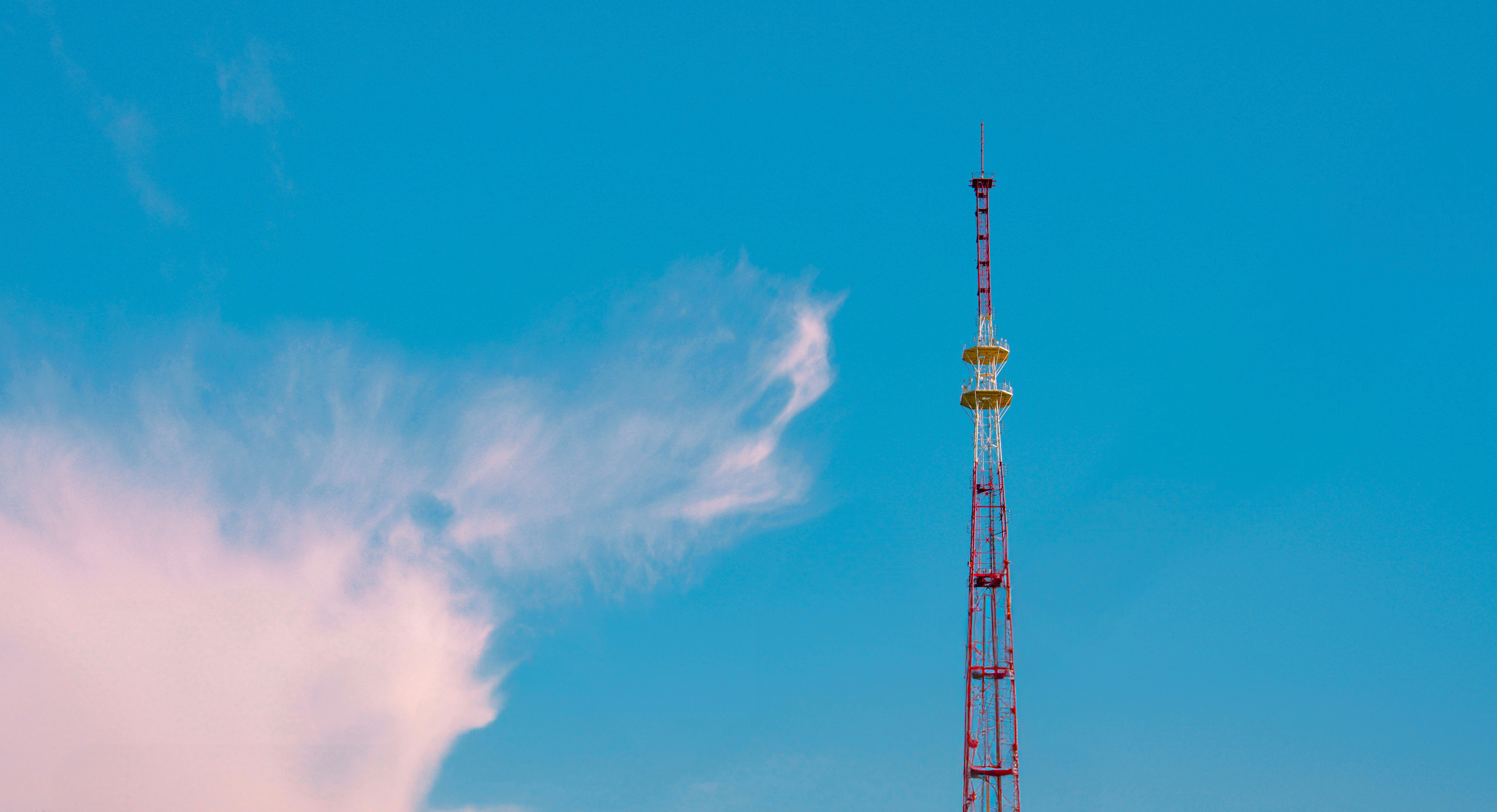 Tall radio mast rising into a vivid blue sky with a hint of pink clouds to the left, emphasizing architectural structure and negative space.