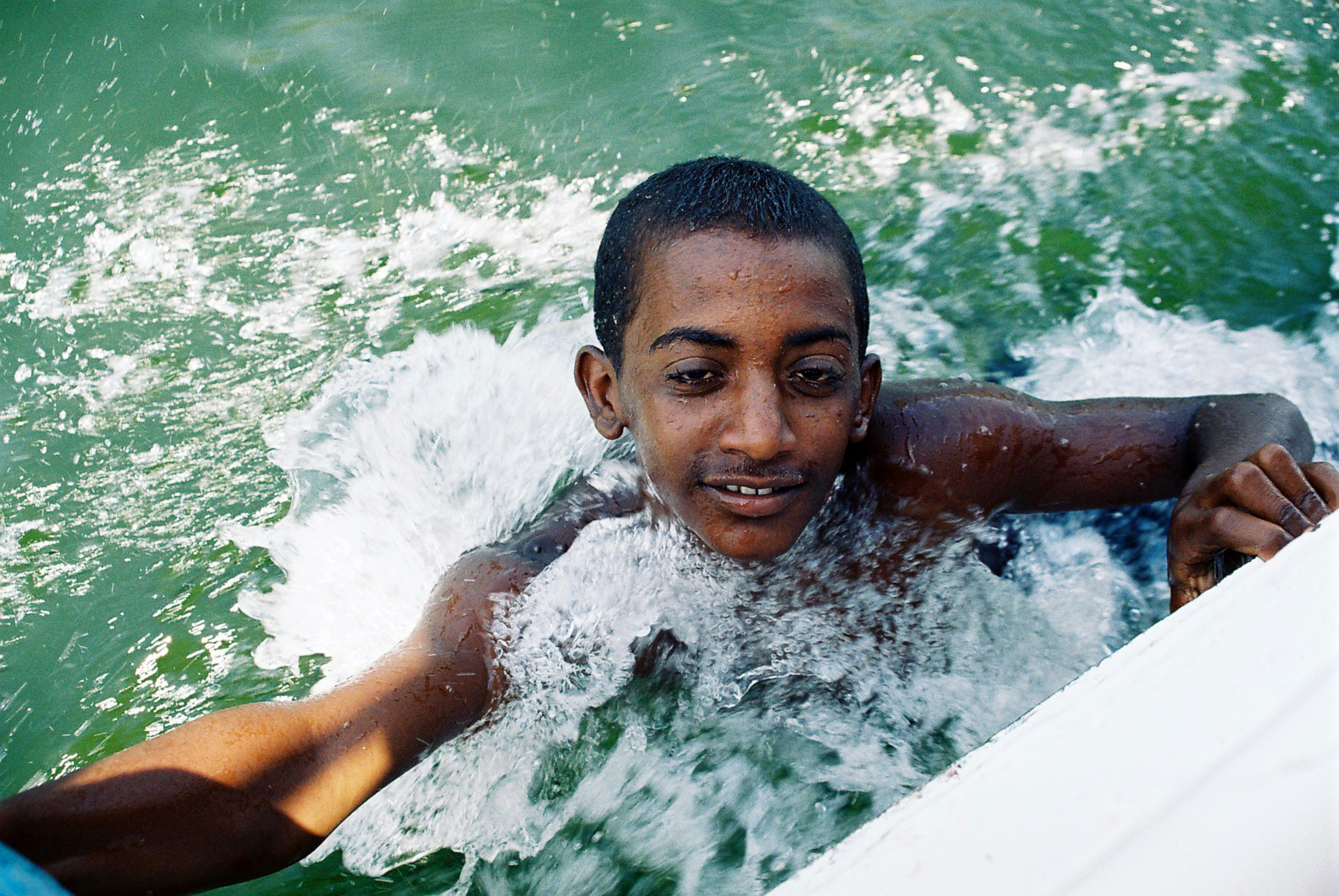 Grasp on the Waves: a swimmer clings to the bow at sea level