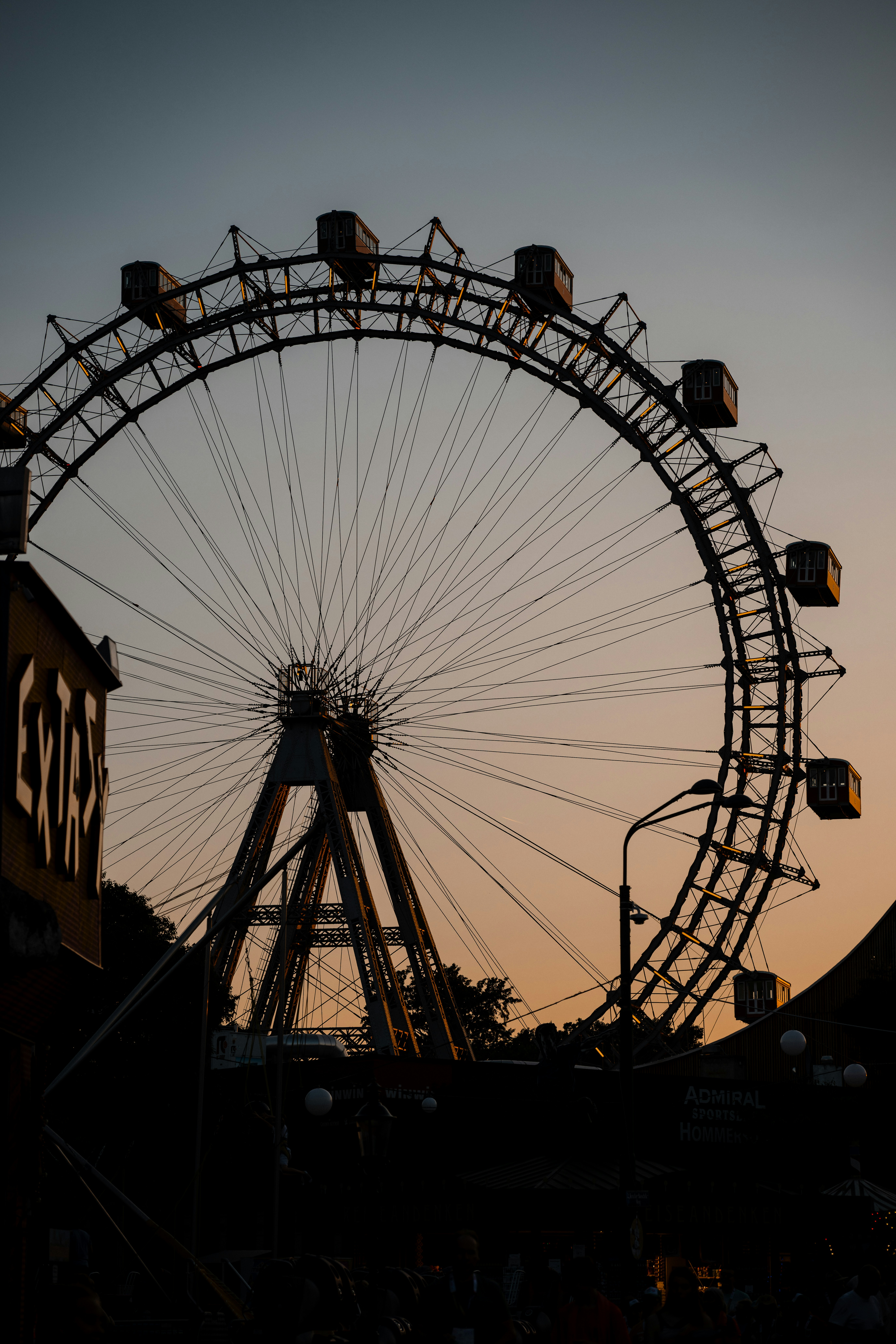 Silhouette of a towering Ferris wheel against a warm dusk sky