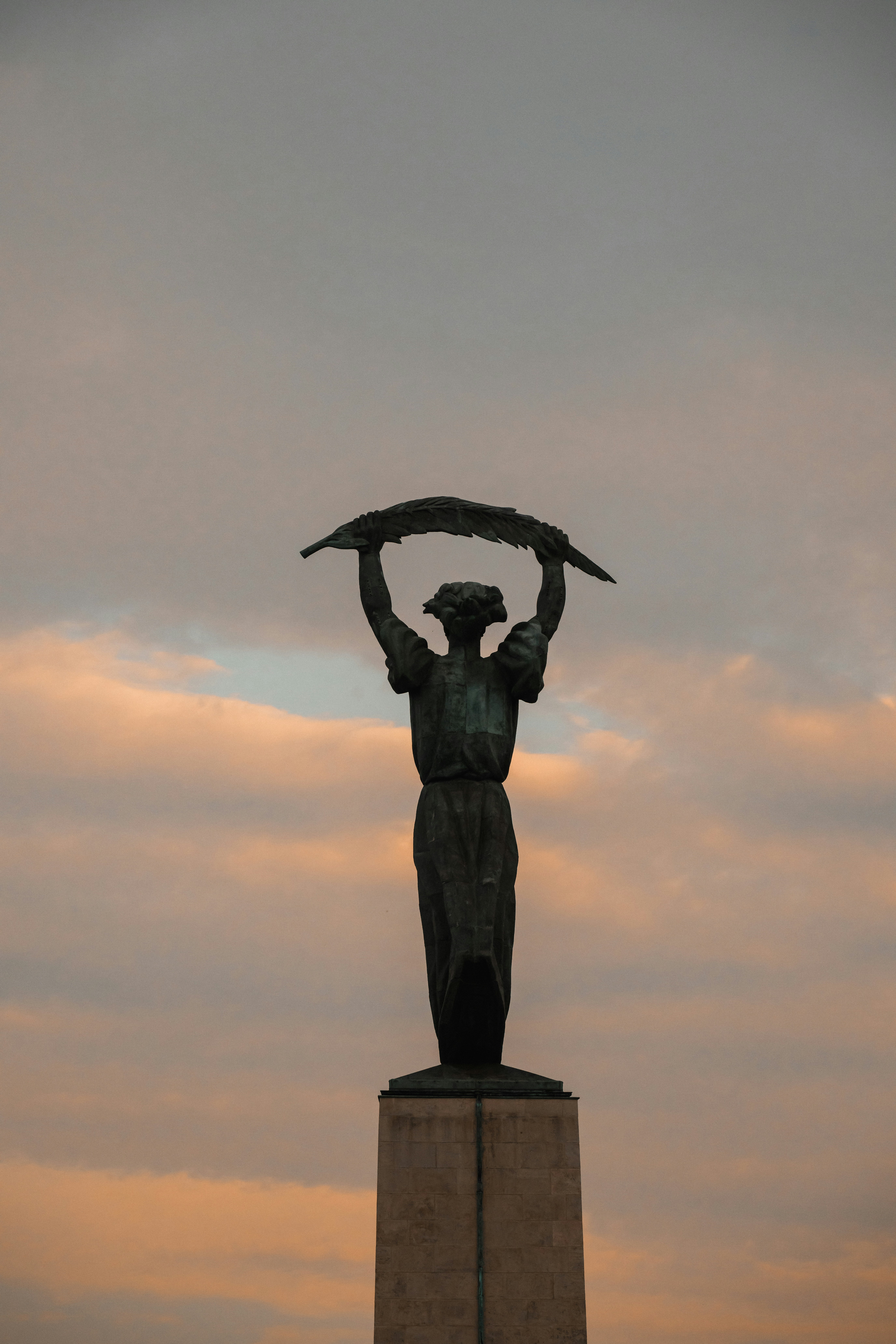 Rising Hope: A Silhouetted Guardian Above the Plinth at Sunset