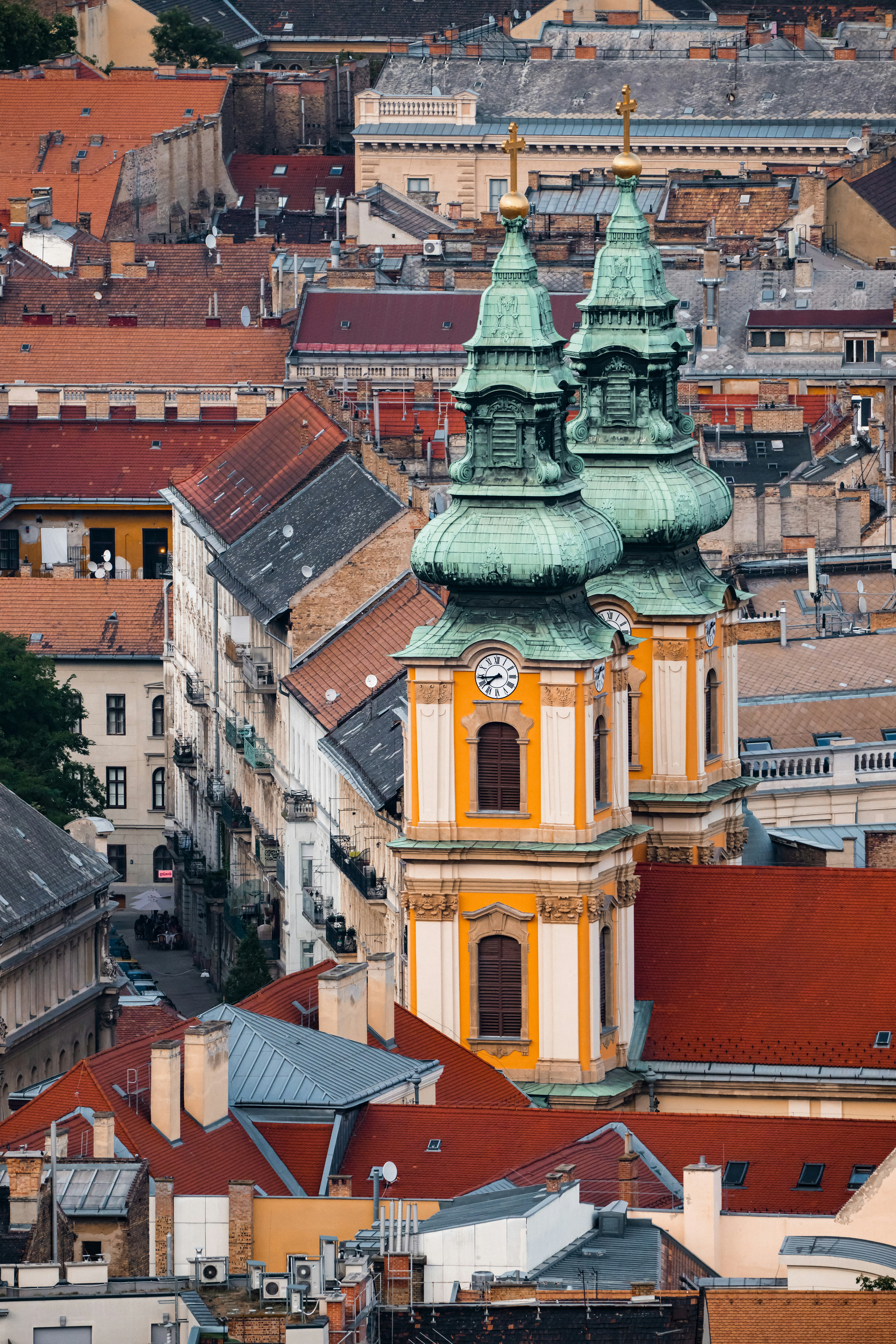 Two Turreted Clock Towers Rising Above a Tiled City Roofscape