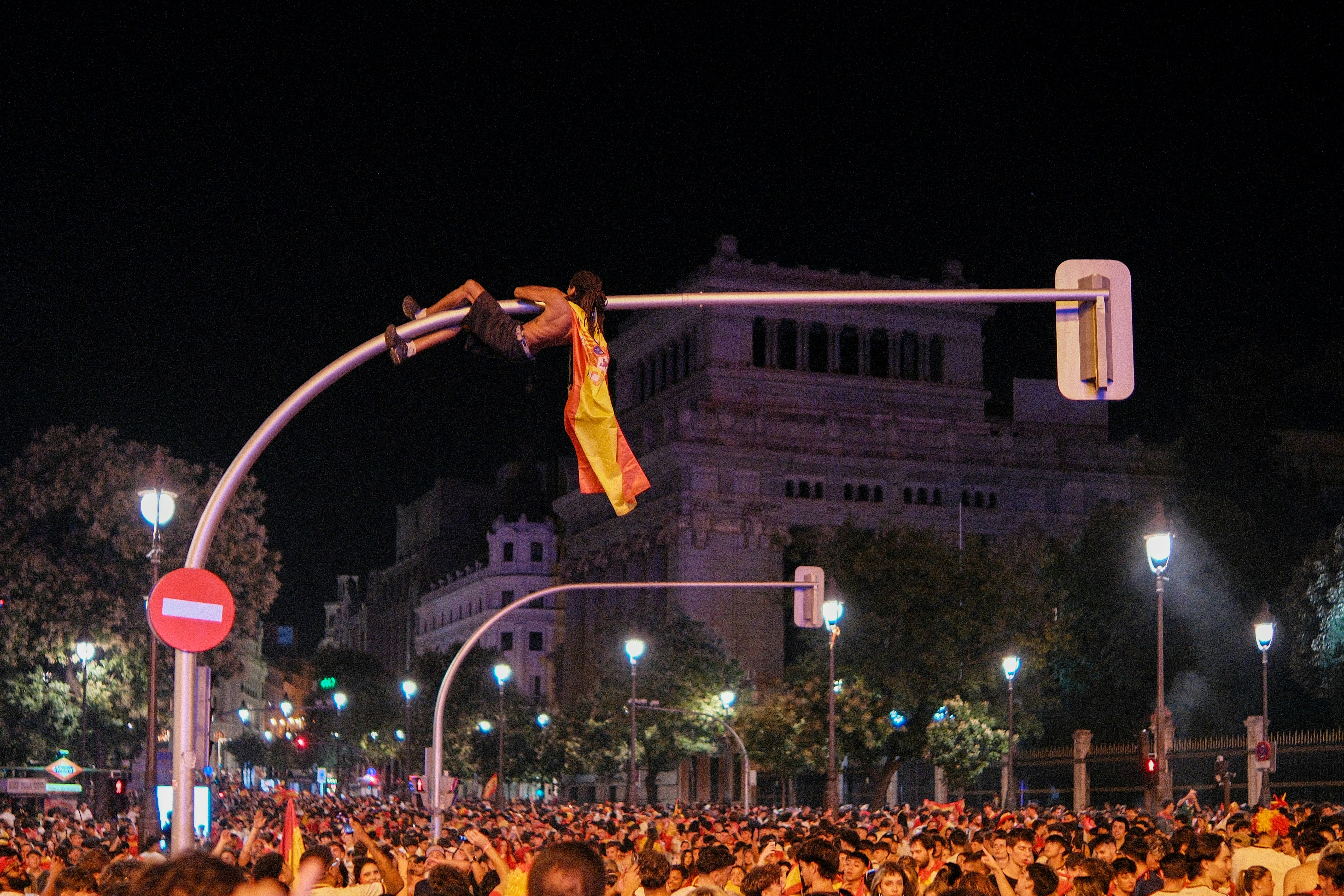 Night Dare on the Crosswalk: A Acrobat Climbs the Street Light Over a Sea of Lights