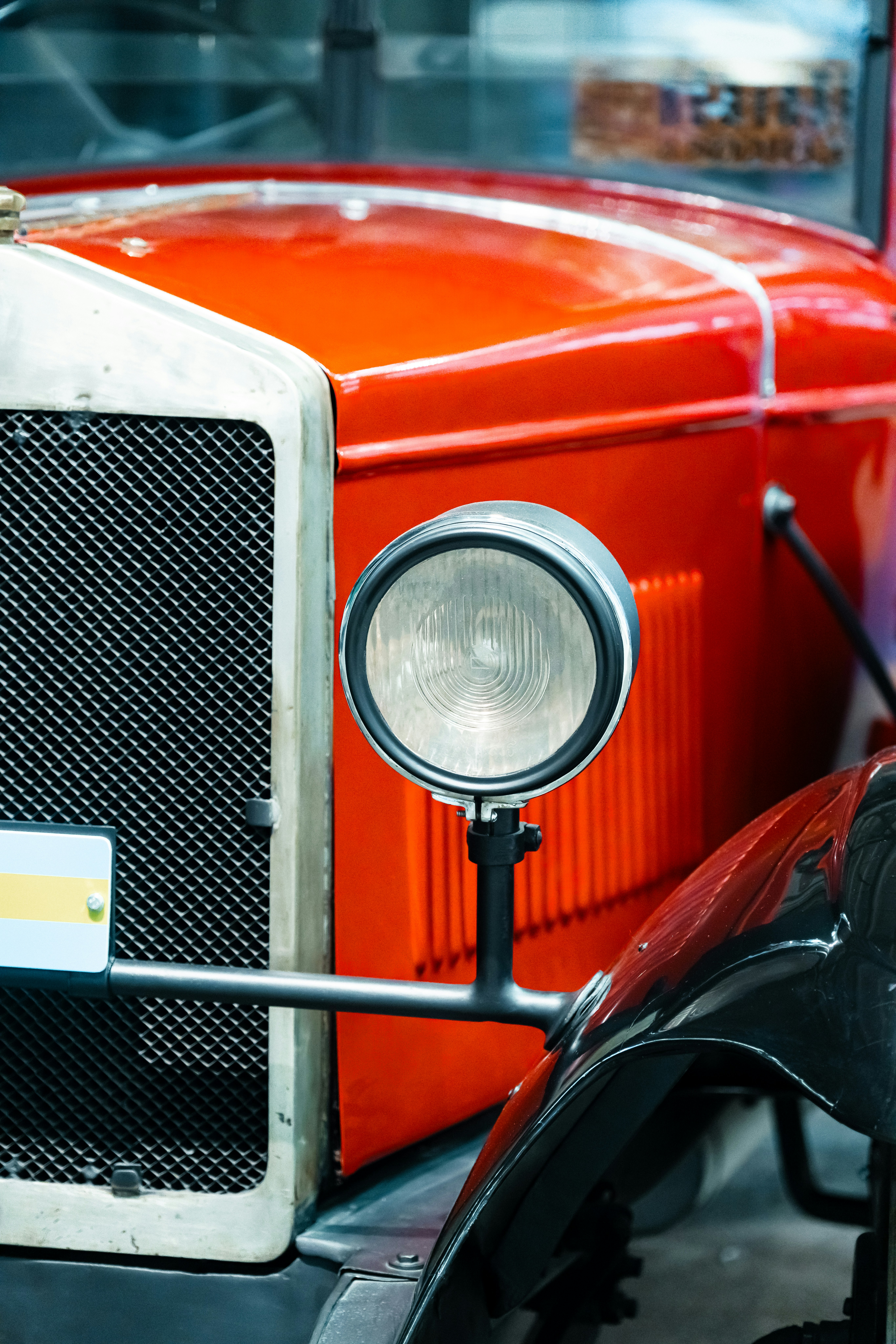 Vintage Red Car Headlamp in Focus: A Close-Up of Retro Grille and Hood