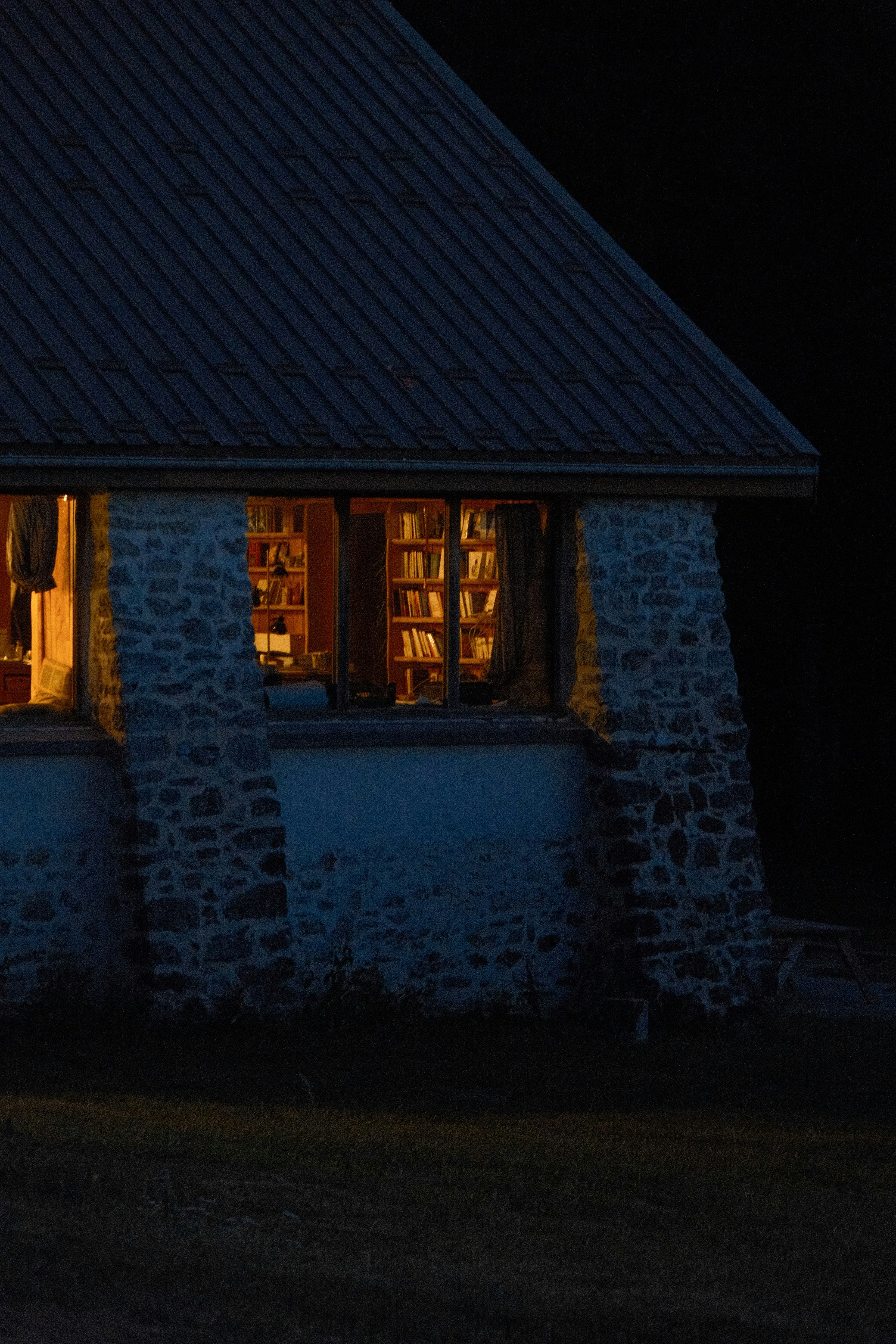Warm Library Glow Through a Windowed Cottage