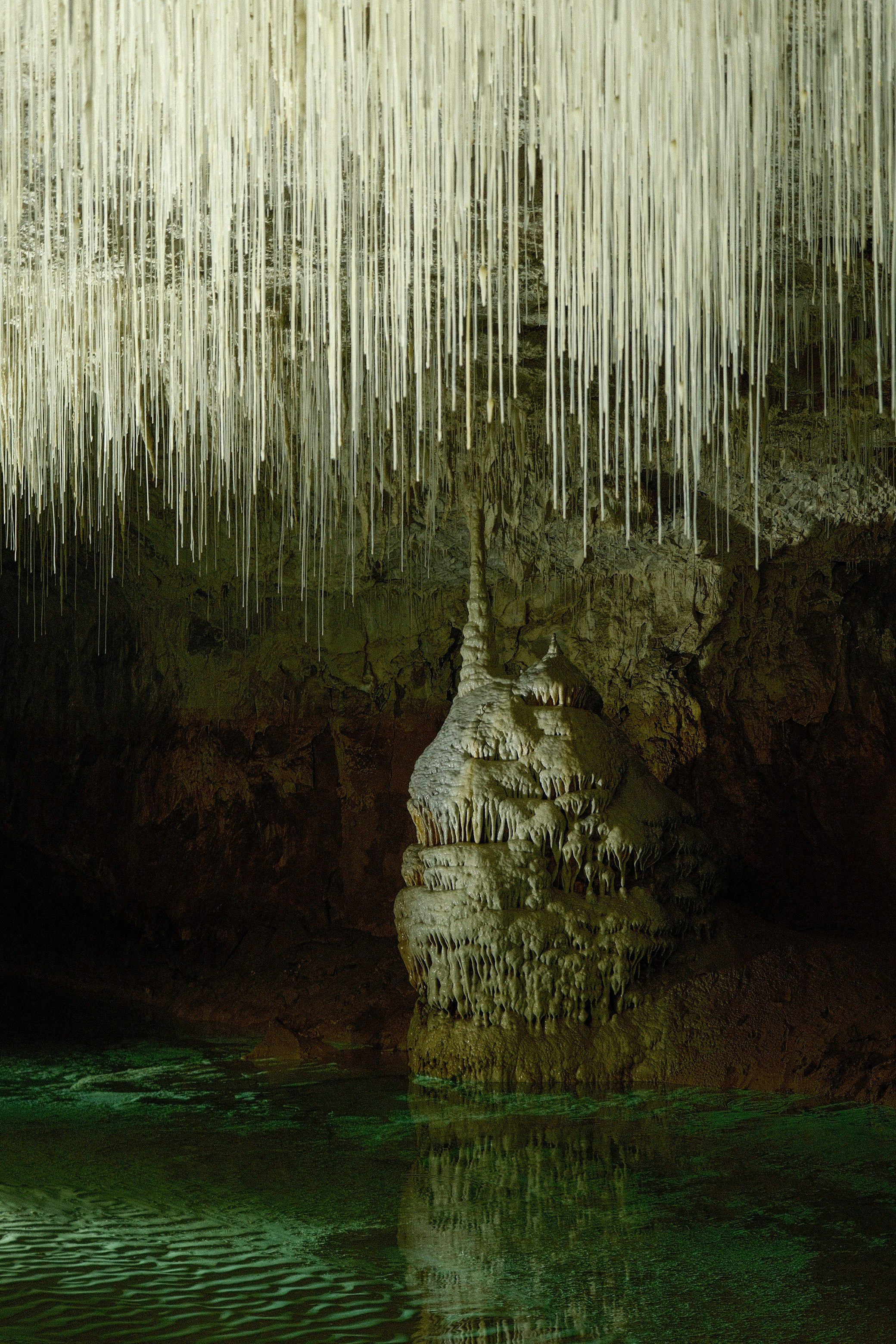 Stalactite Cathedral: A Towering Speleothem Surrounded by Dark Mirror Water
