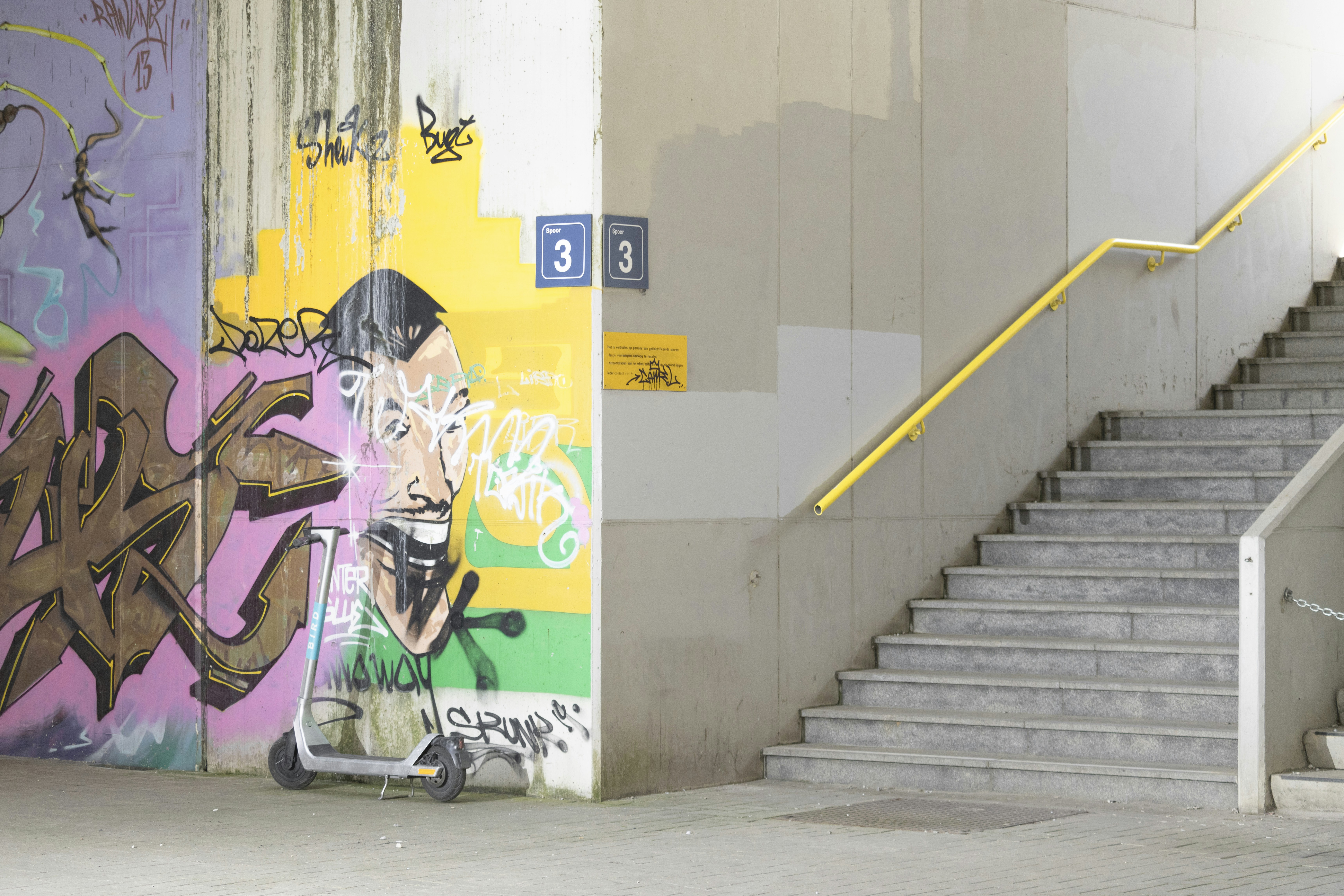 Urban scene with graffiti wall, scooter, and concrete staircase.