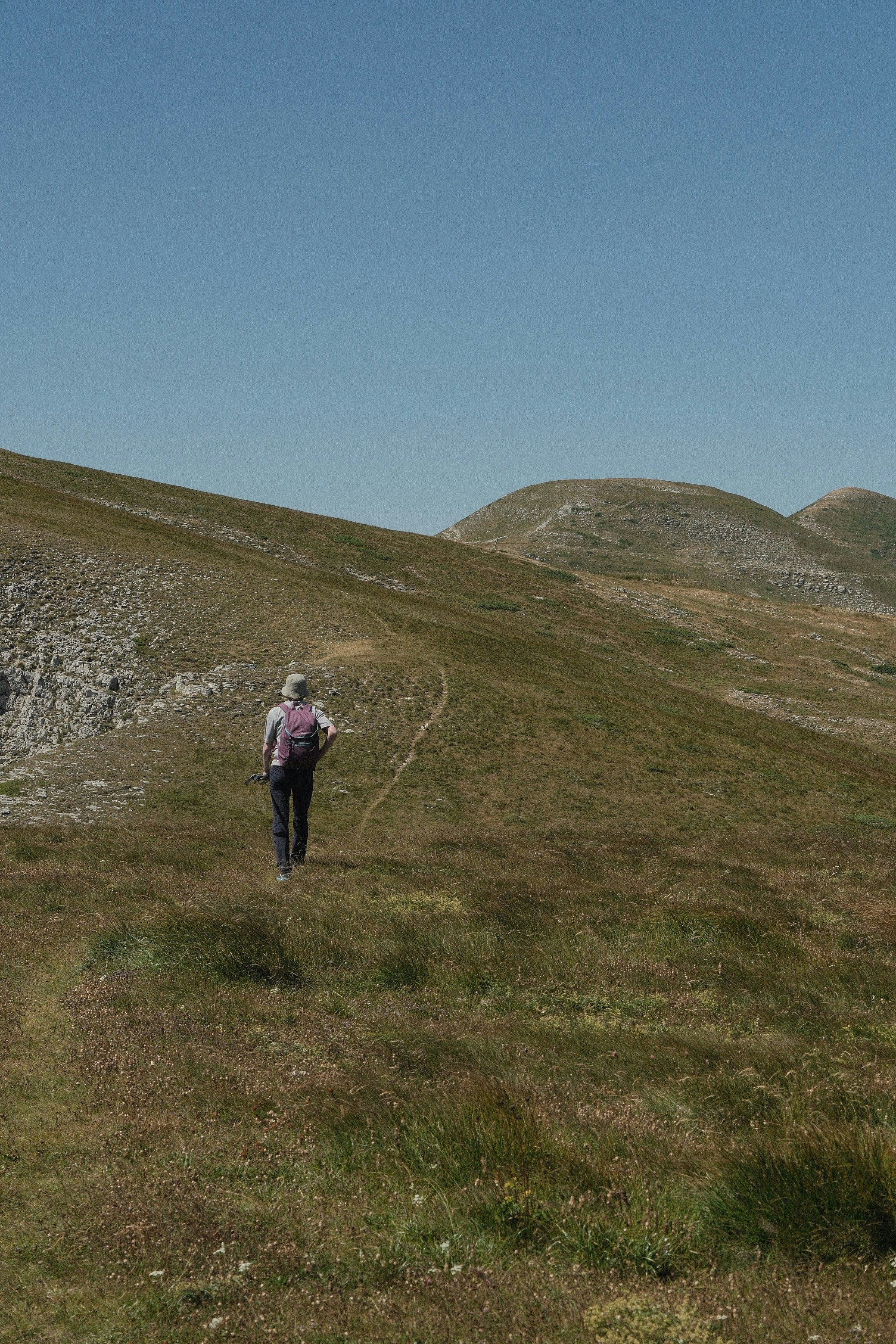 Trail to the Quiet Summit: A Lone Hiker Amid Open Moorland