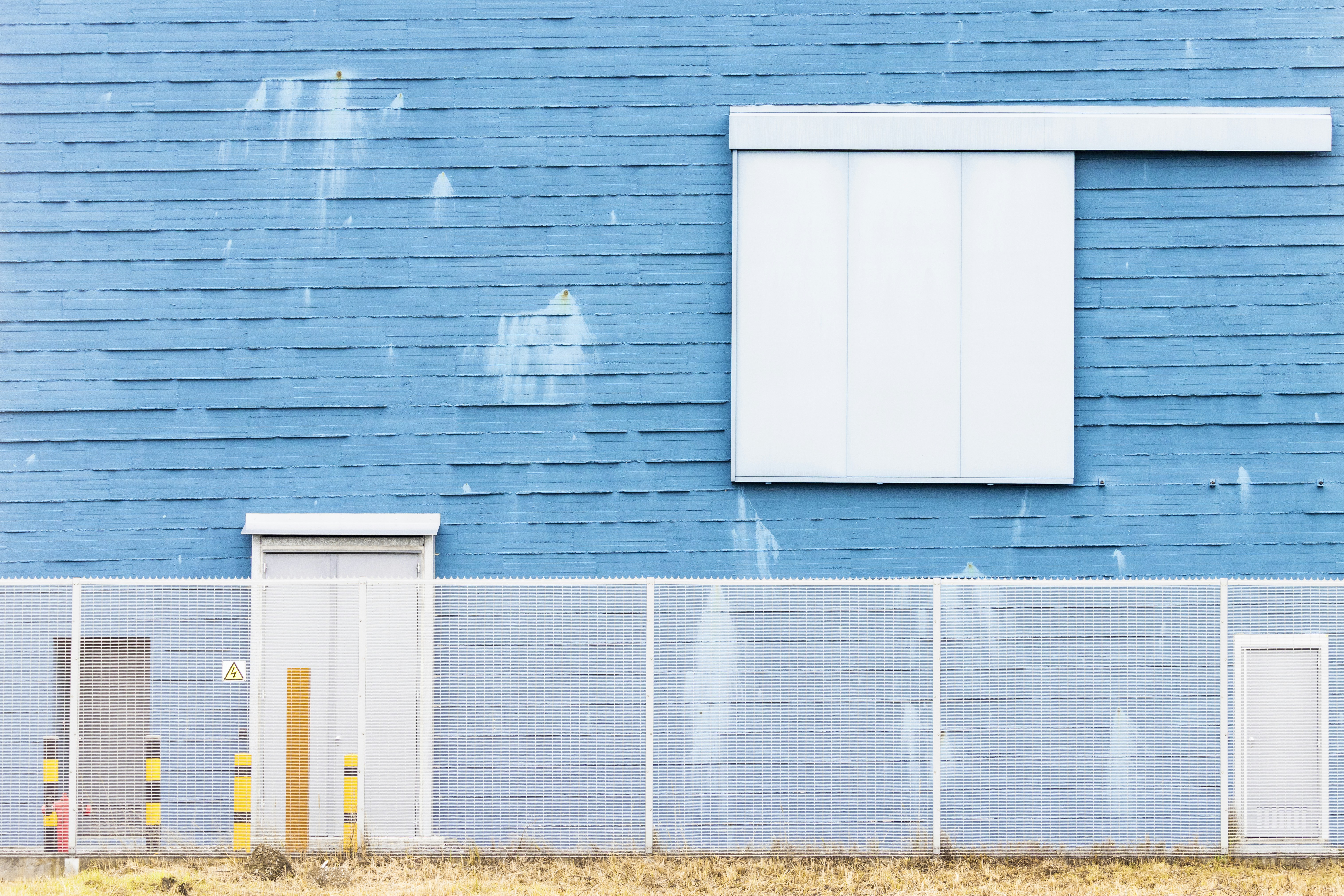 Blue Warehouse Portrait: The Quiet Facade Under a Glaring Window