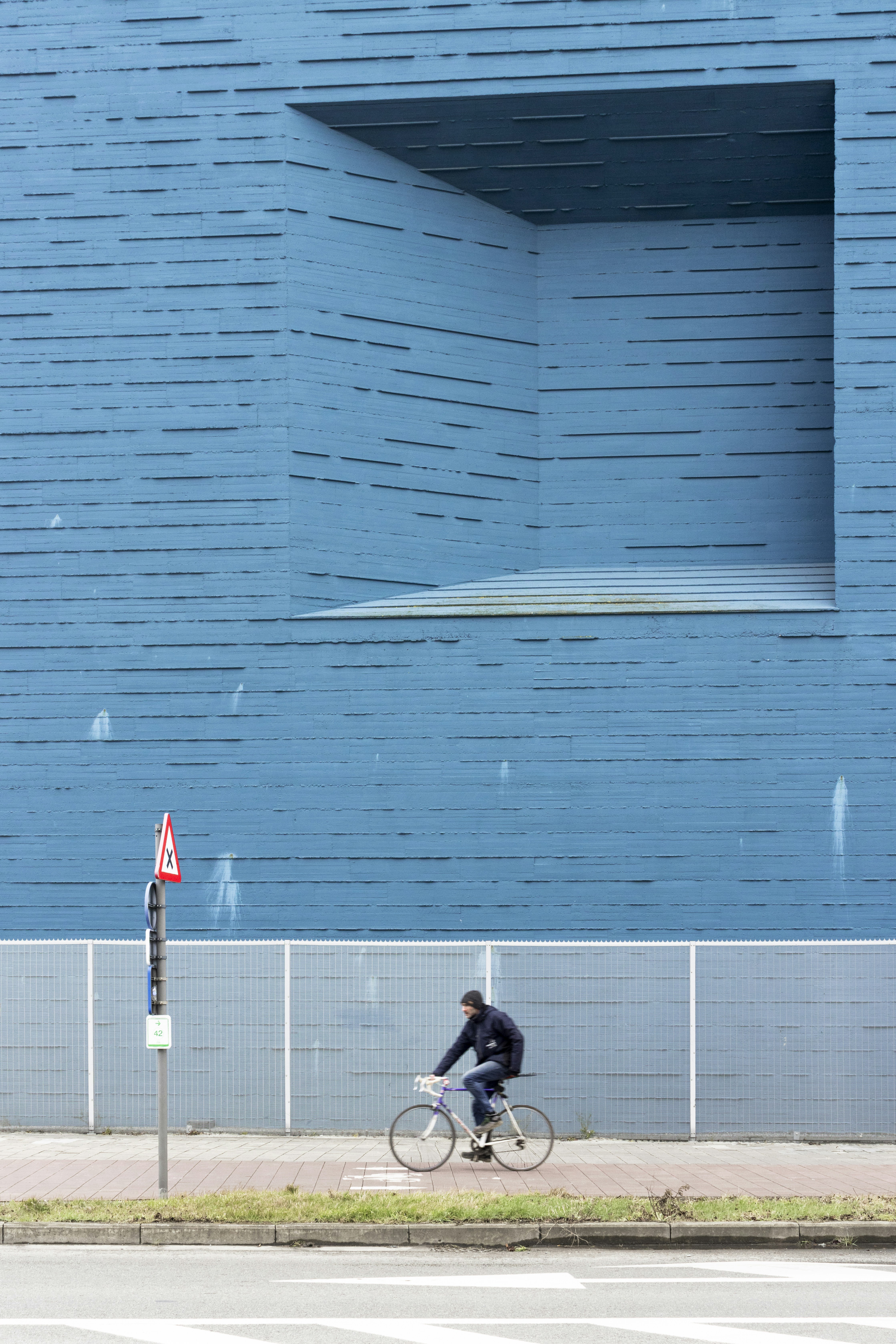 Blue Brick Quiet: A Cyclist Passes the Monolithic Wall