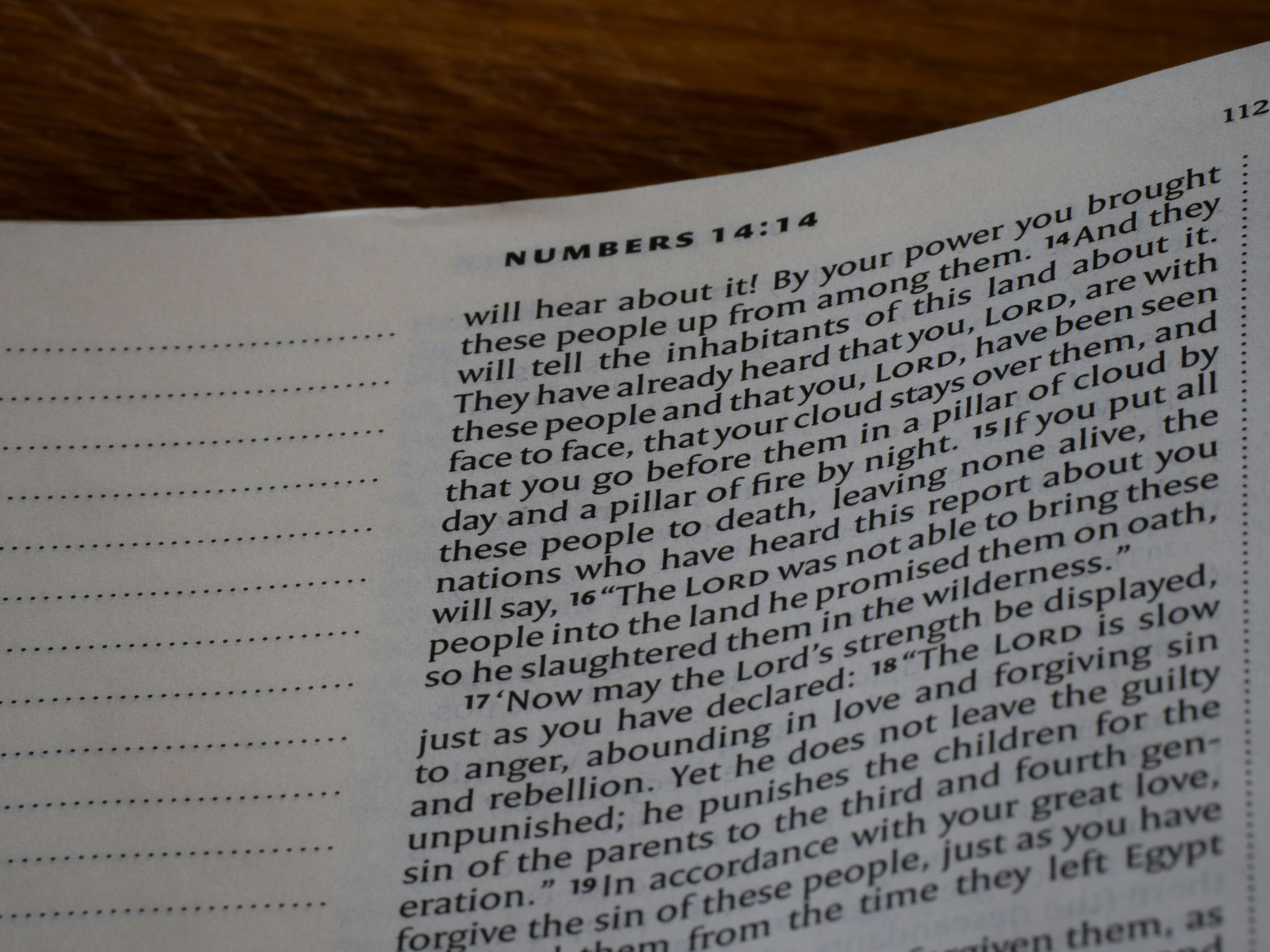 Close-up of a printed page with a surrounding wooden surface; the text forms a diagonal composition, highlighting typography and texture as the subject. (Logo/print) This is a photograph of a printed page with visible grain and ink.