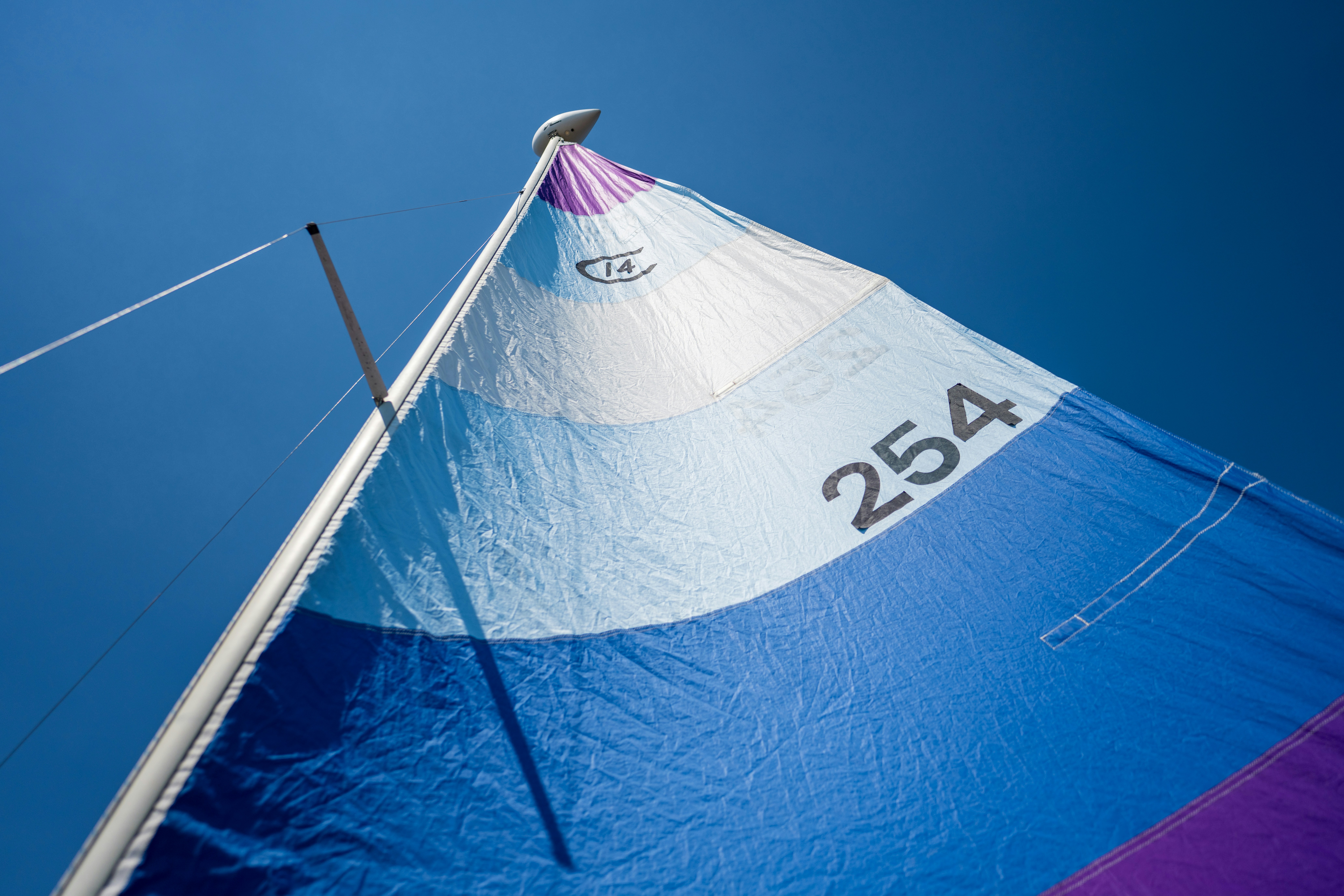 Sail in the Sun: Close-up of a Colorful Windward Sail Against a Clear Sky