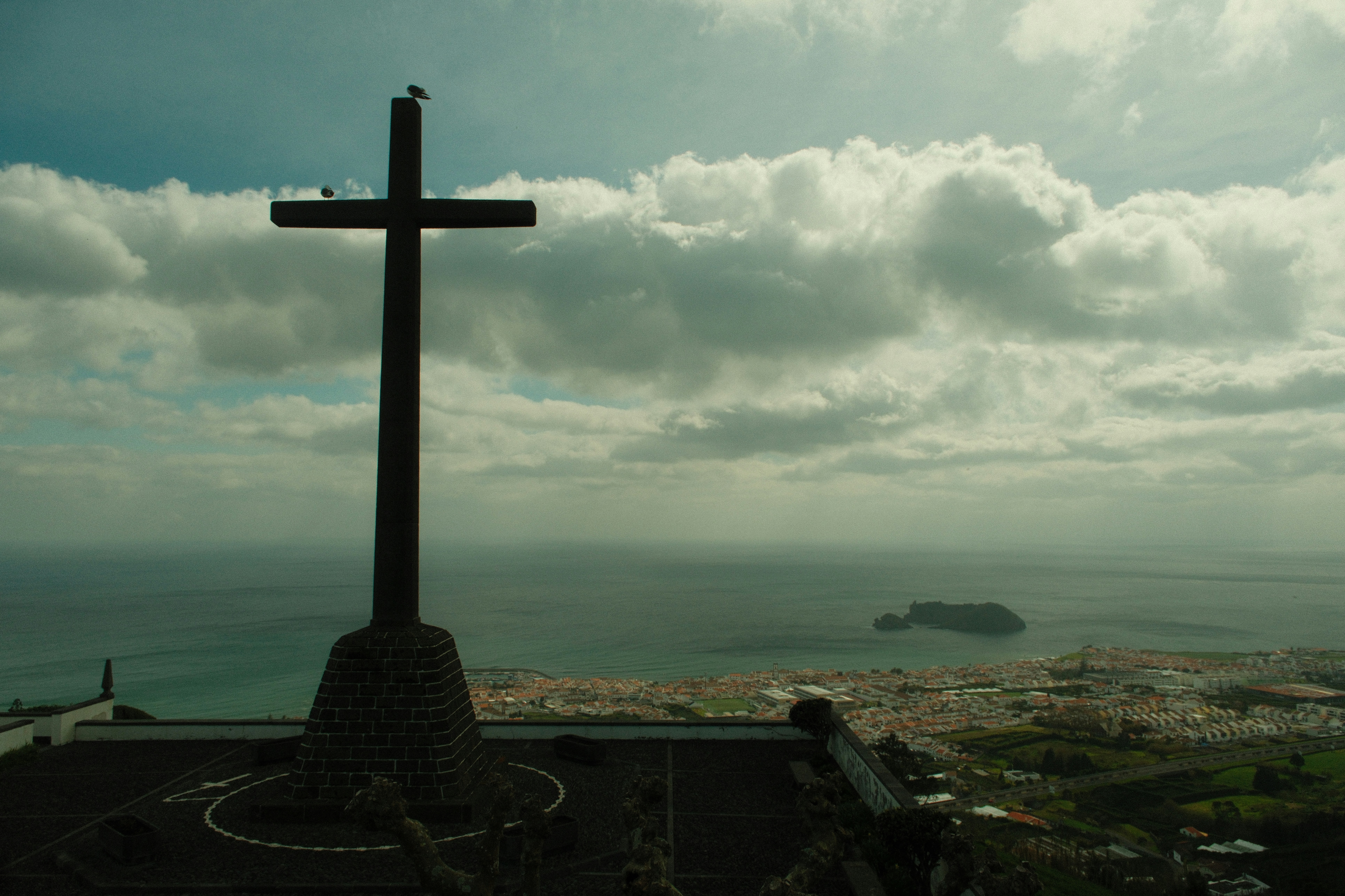 Cross on the Cliff: A Sea Dawn over a Distant Island