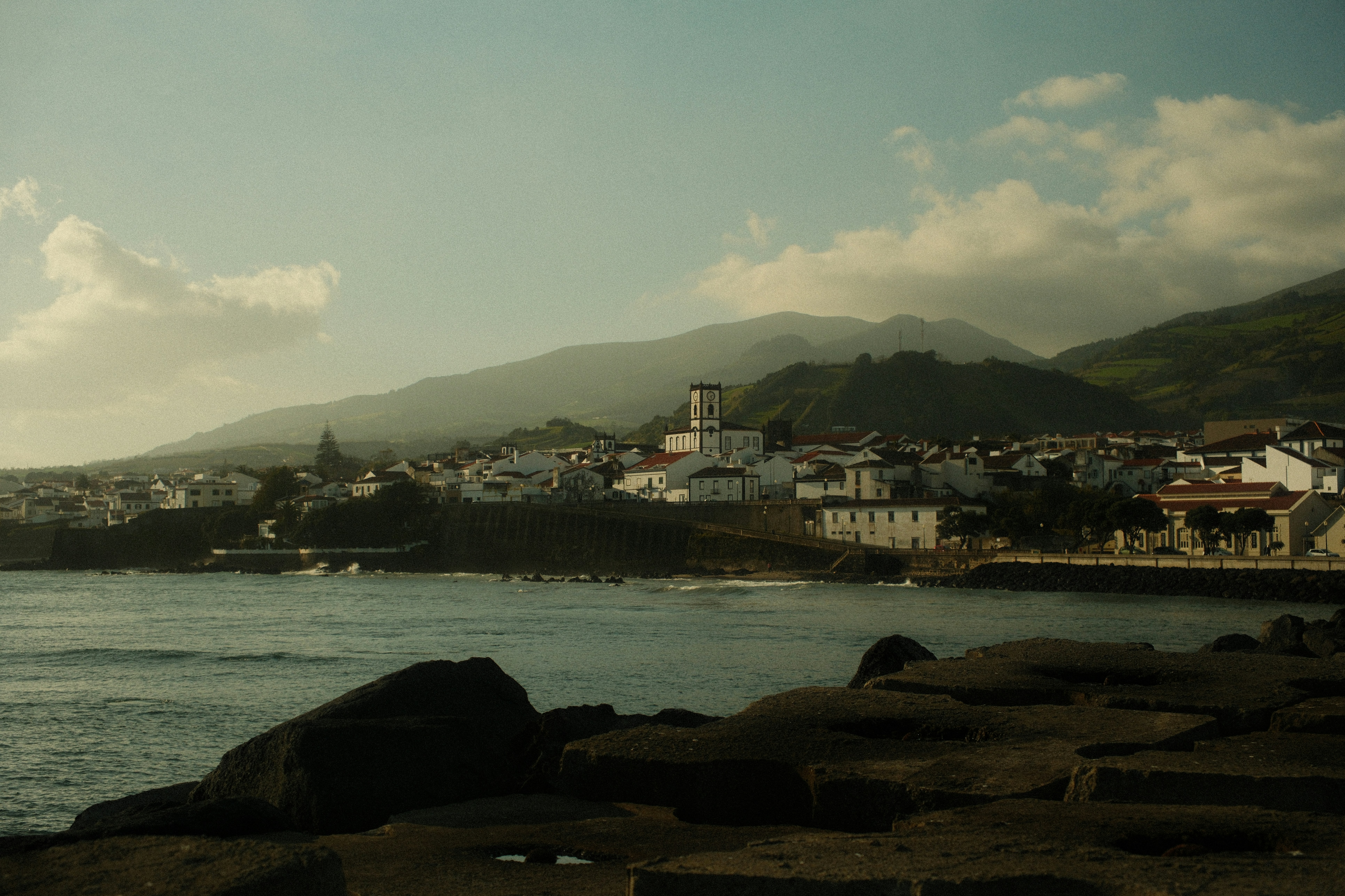 Coastal Village at Dusk: Quiet Harbor Beneath Rolling Hills