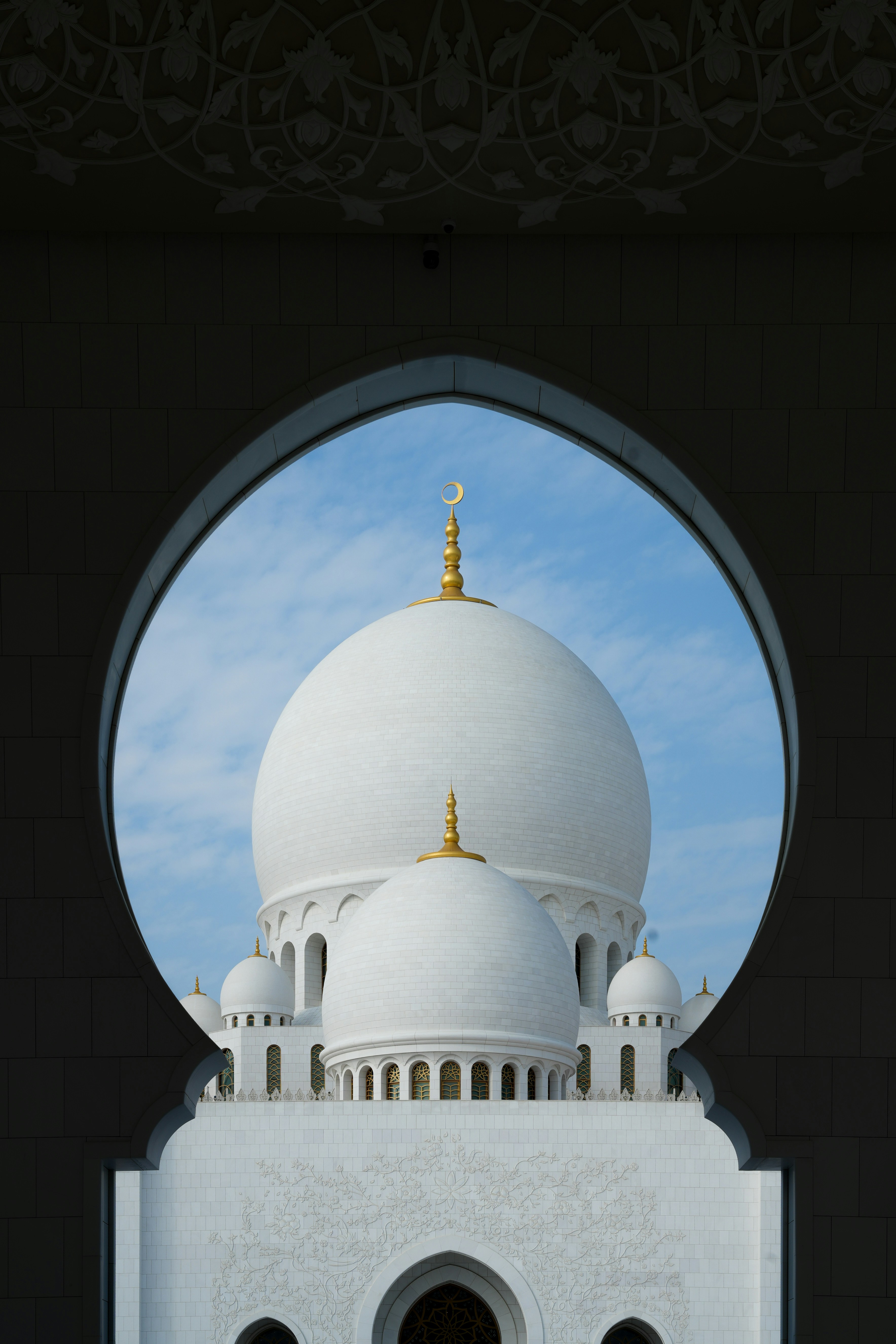 White domes under a blue sky framed by an arched gateway