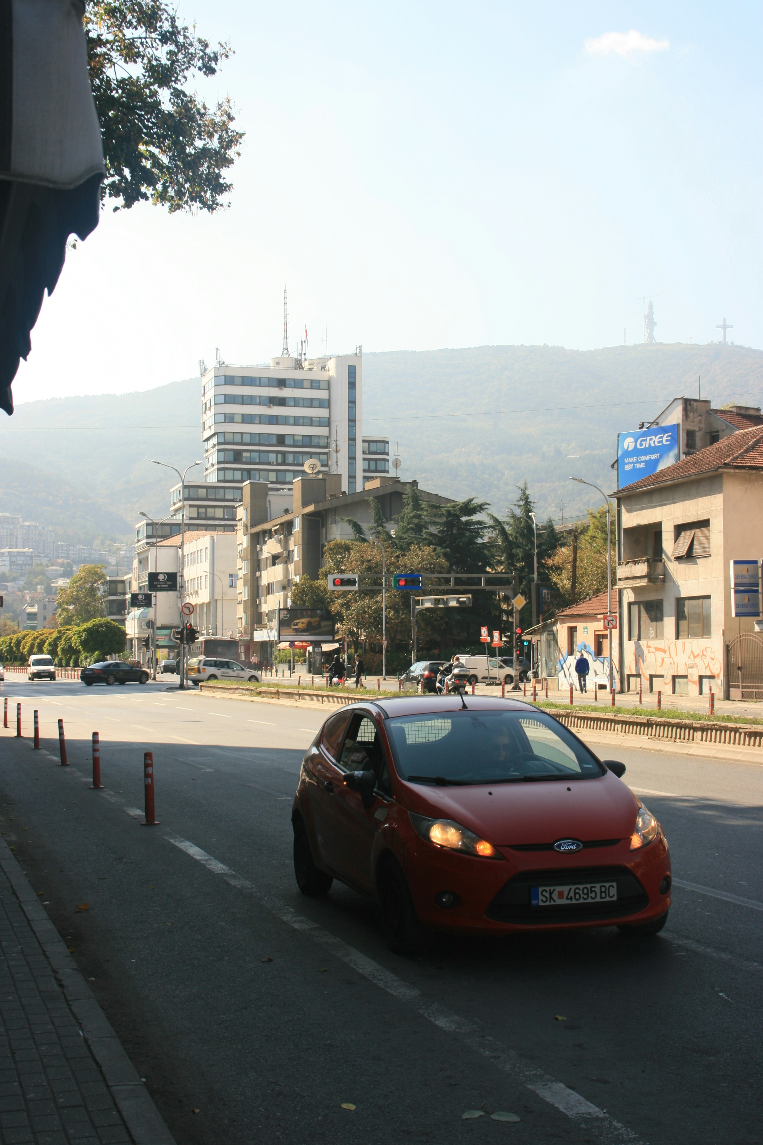 Red City Car on a Busy Street in Morning Light