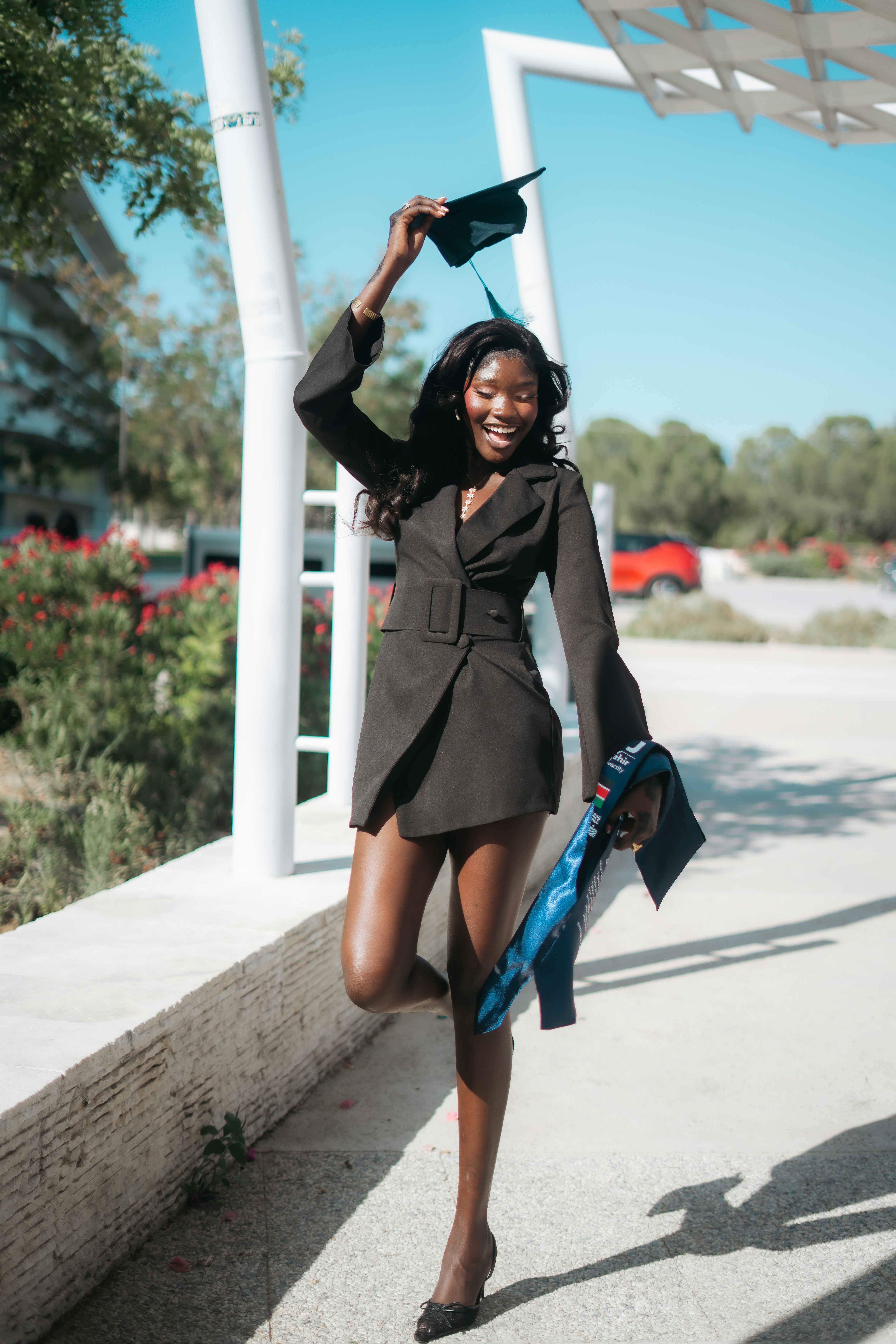 Graduate in Motion: A Victory Pose Under Bright Sky