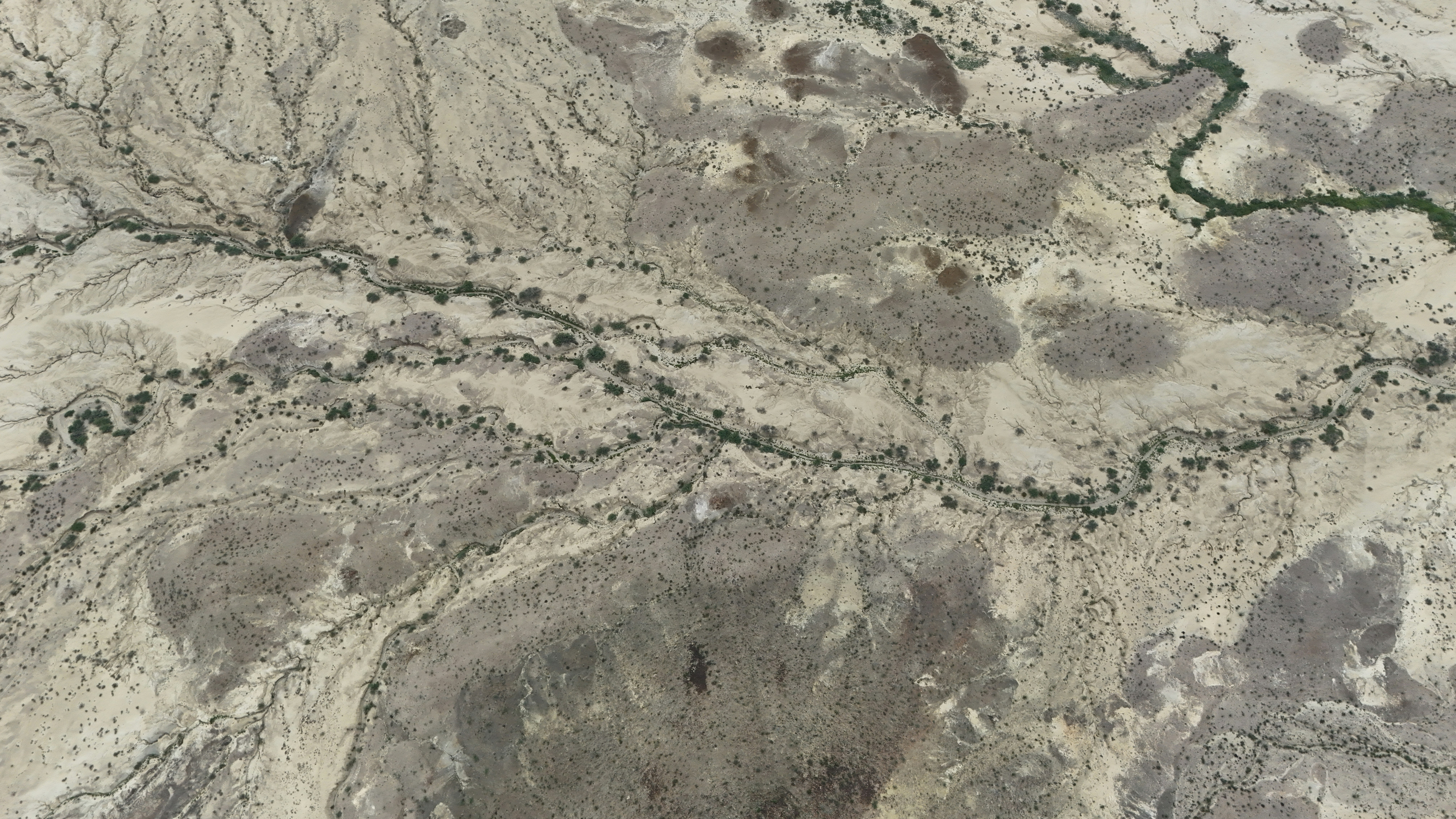 Dry riverbed wake: wind-carved stone ribbons across arid canyon