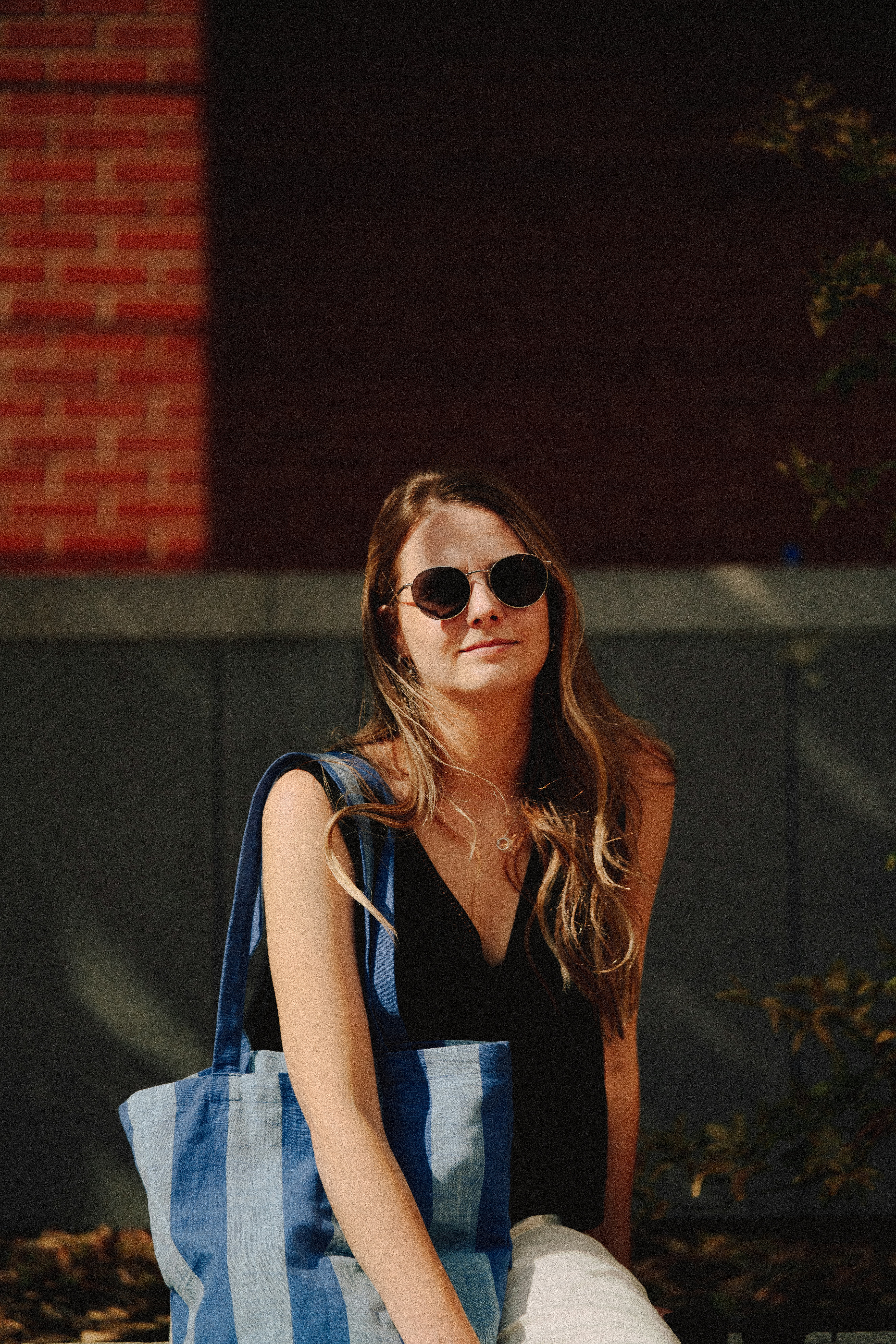 Sunlit Confidence: A Portrait with Striped Tote and Round Sunglasses