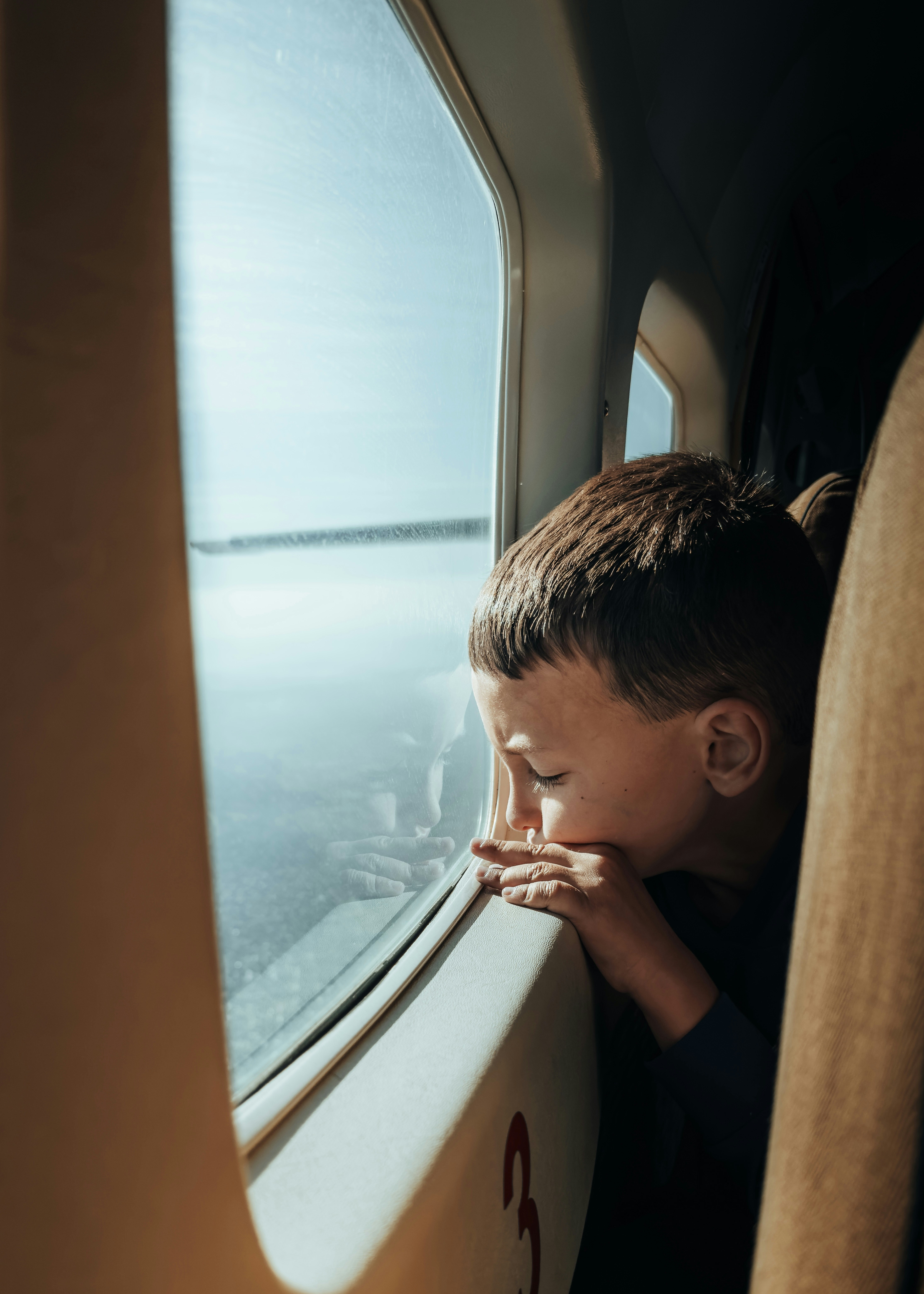 Near the Window: A Boy's Quiet Gaze on the Flight Path