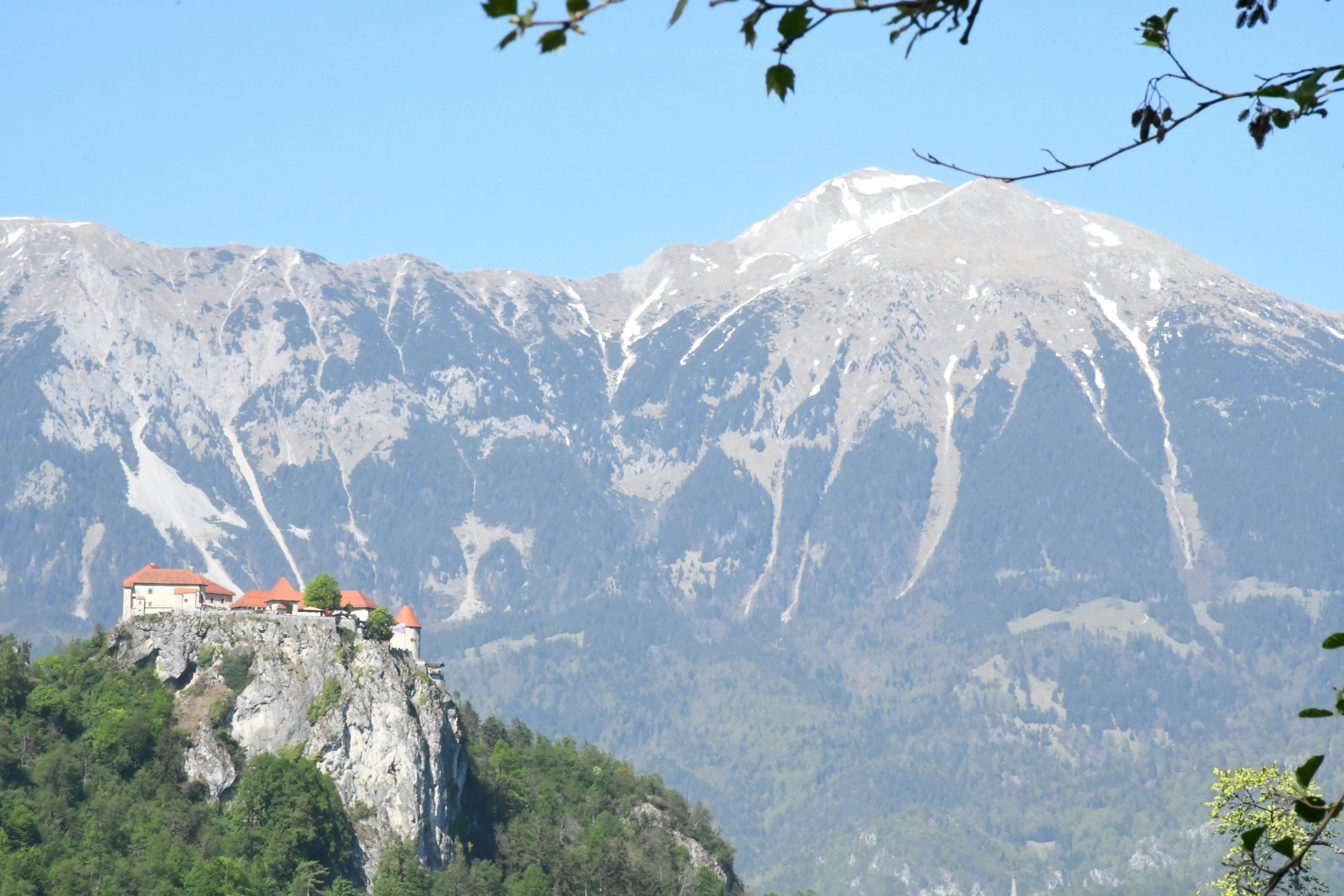 Castle Perched on a Cliff Under Snow-Capped Peaks