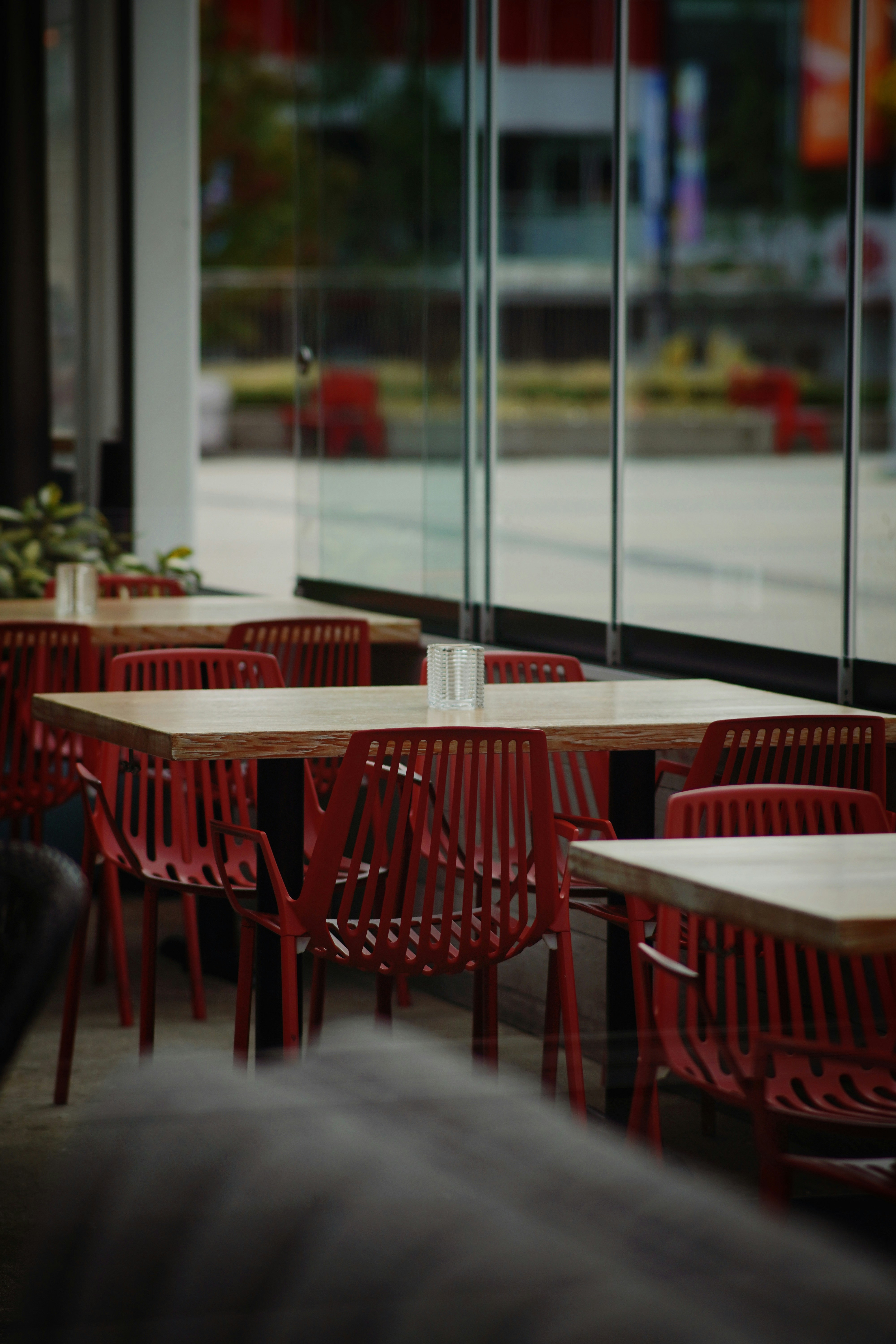 Quiet Café Terrace in Red Chairs Under Glass Walls
