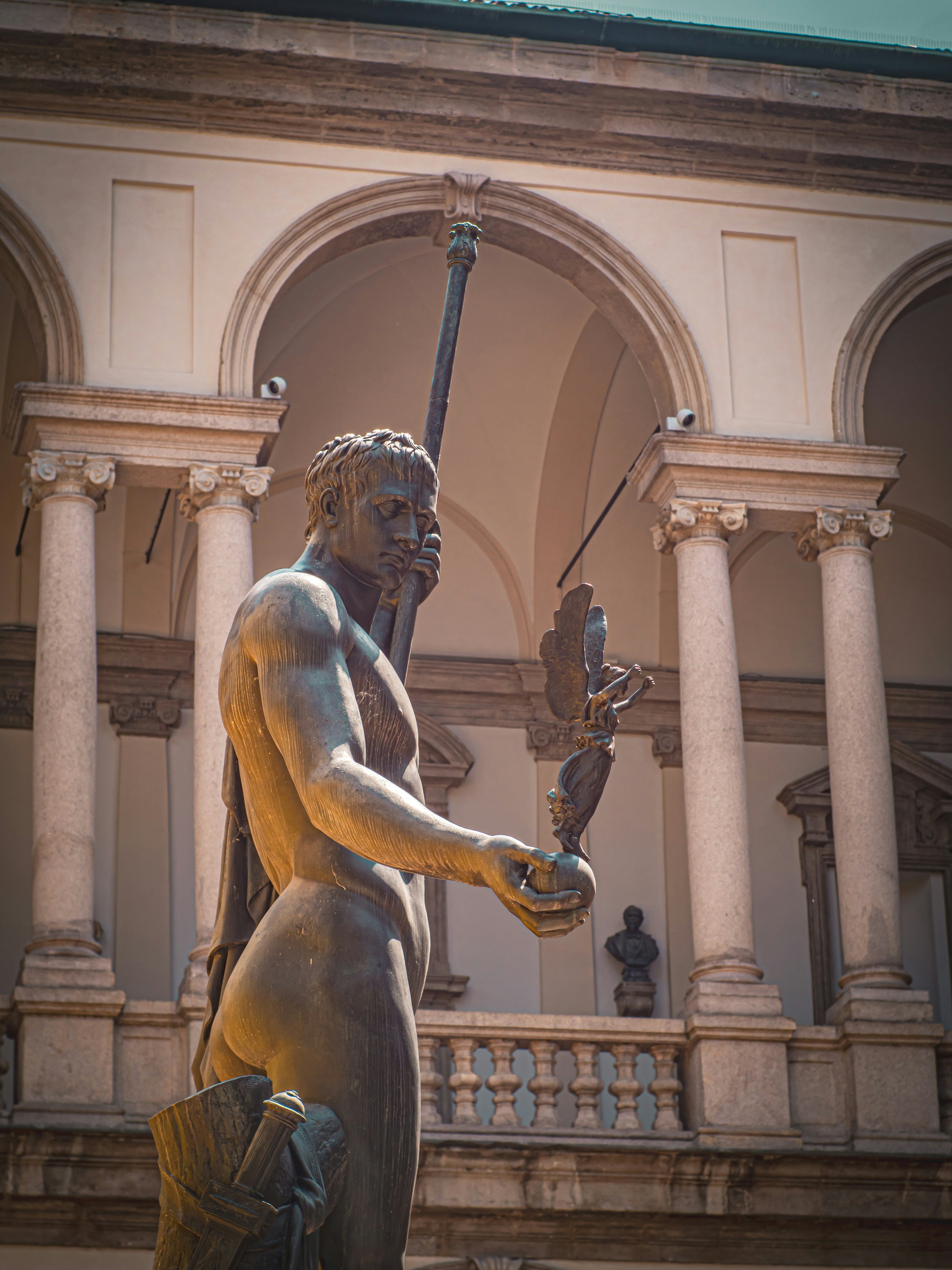 Bronze Muse Under Arcades: A Statue with a Winged Gesture
