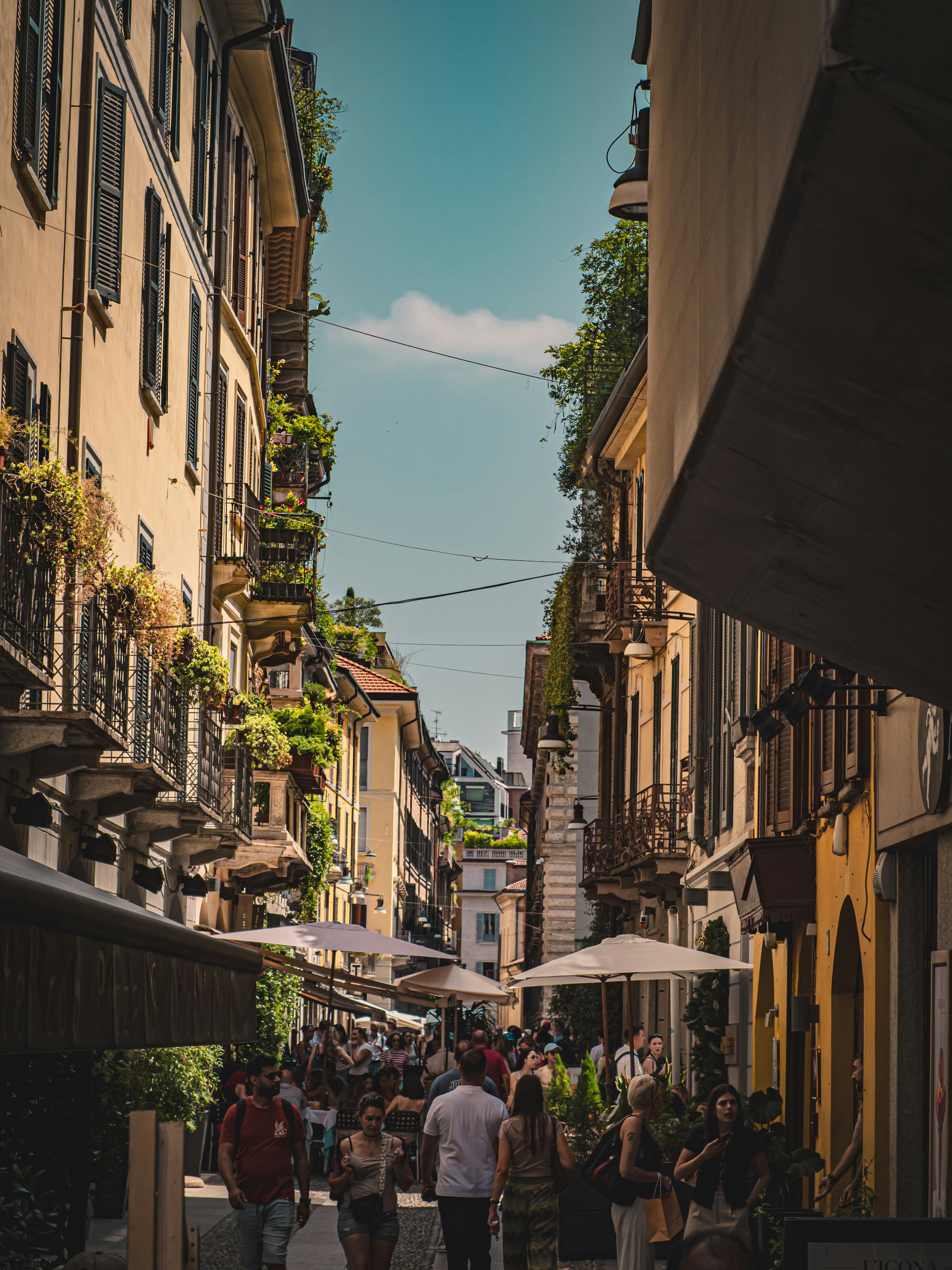 A Sunlit Alley Awakening: People Trek Through a Mediterranean Street