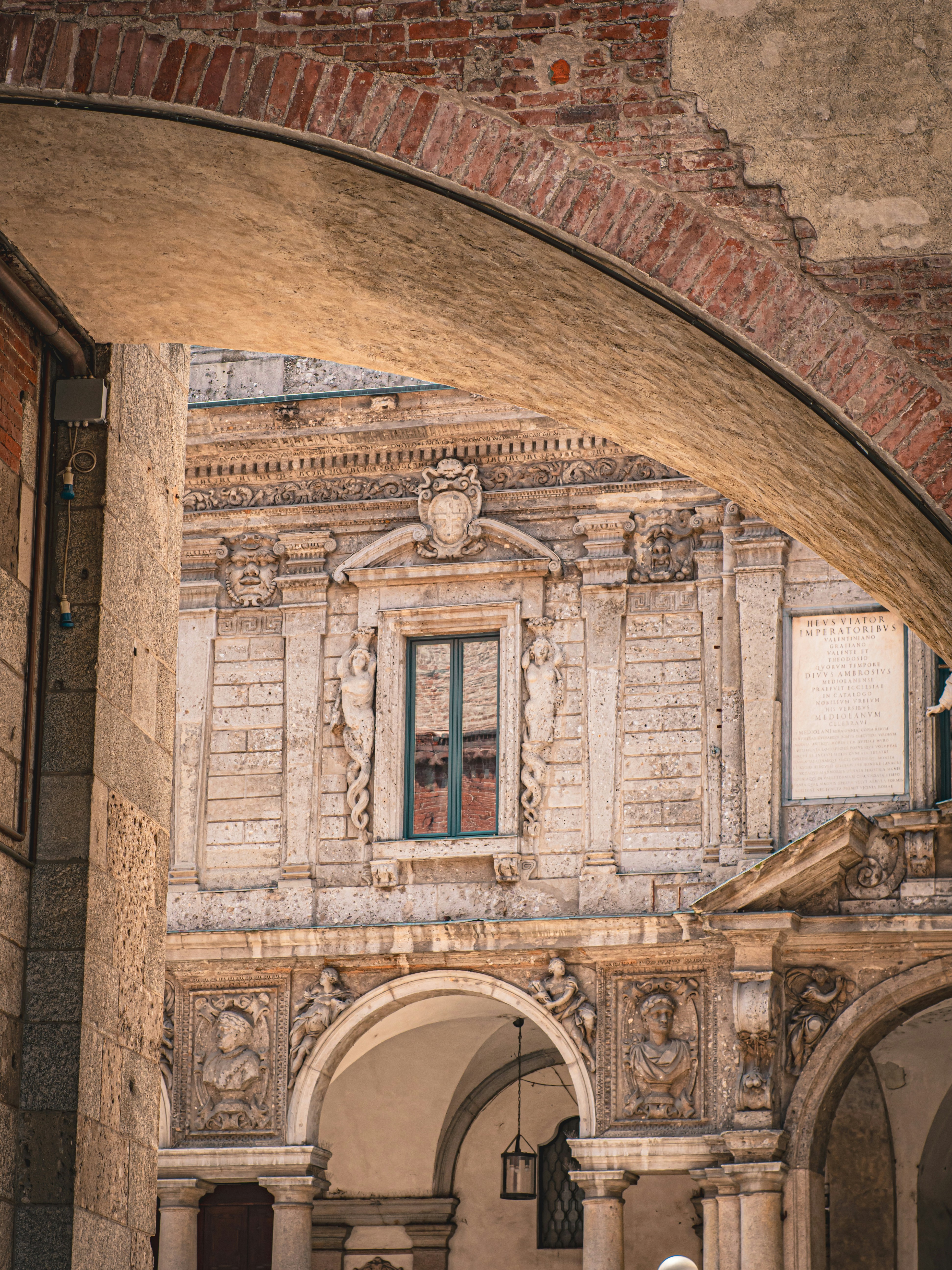 Arched Courtyard Vista: Carved Facade Beneath Brick Archway