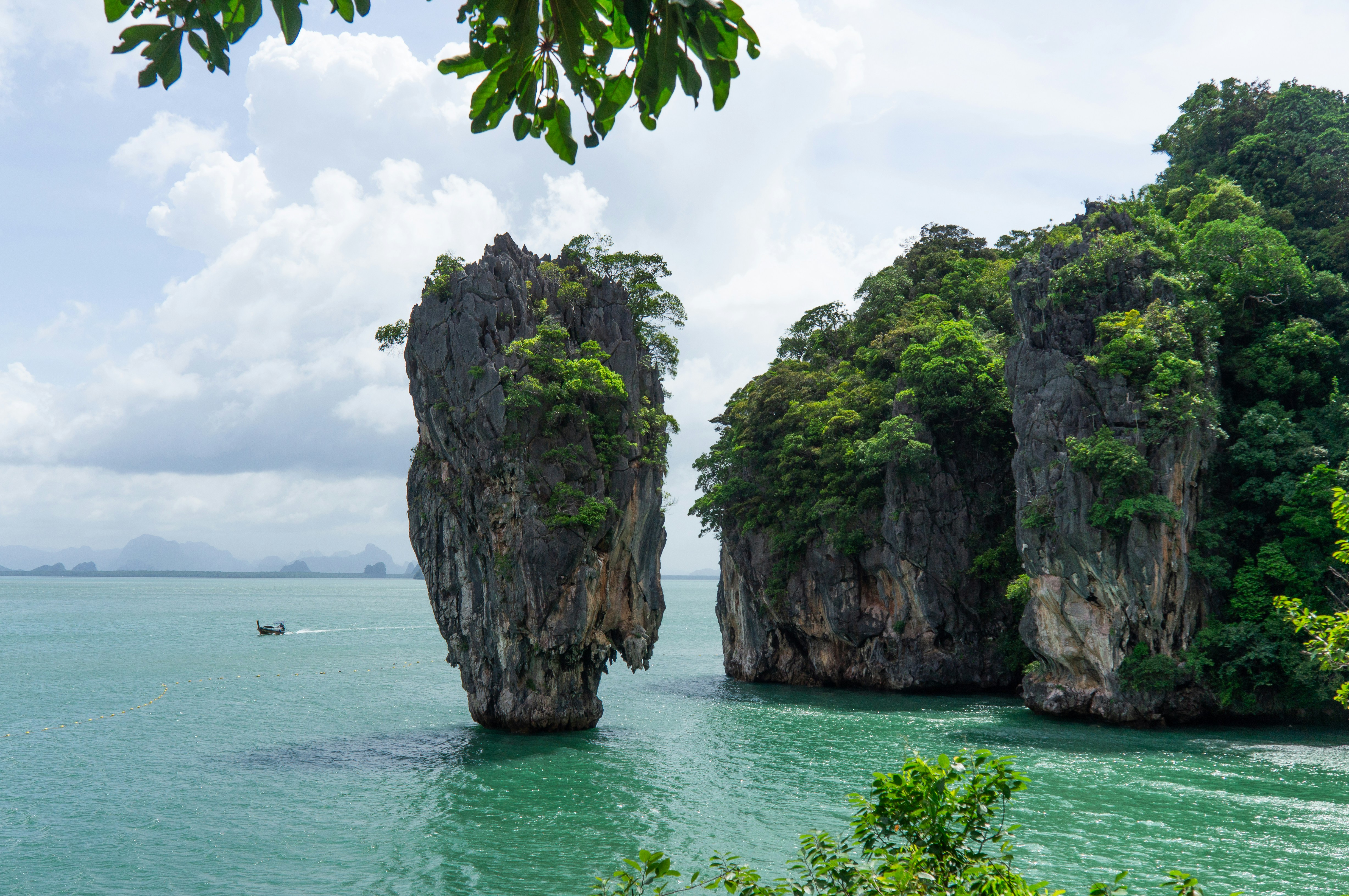 Twin limestone islets in turquoise gulf under leafy canopy