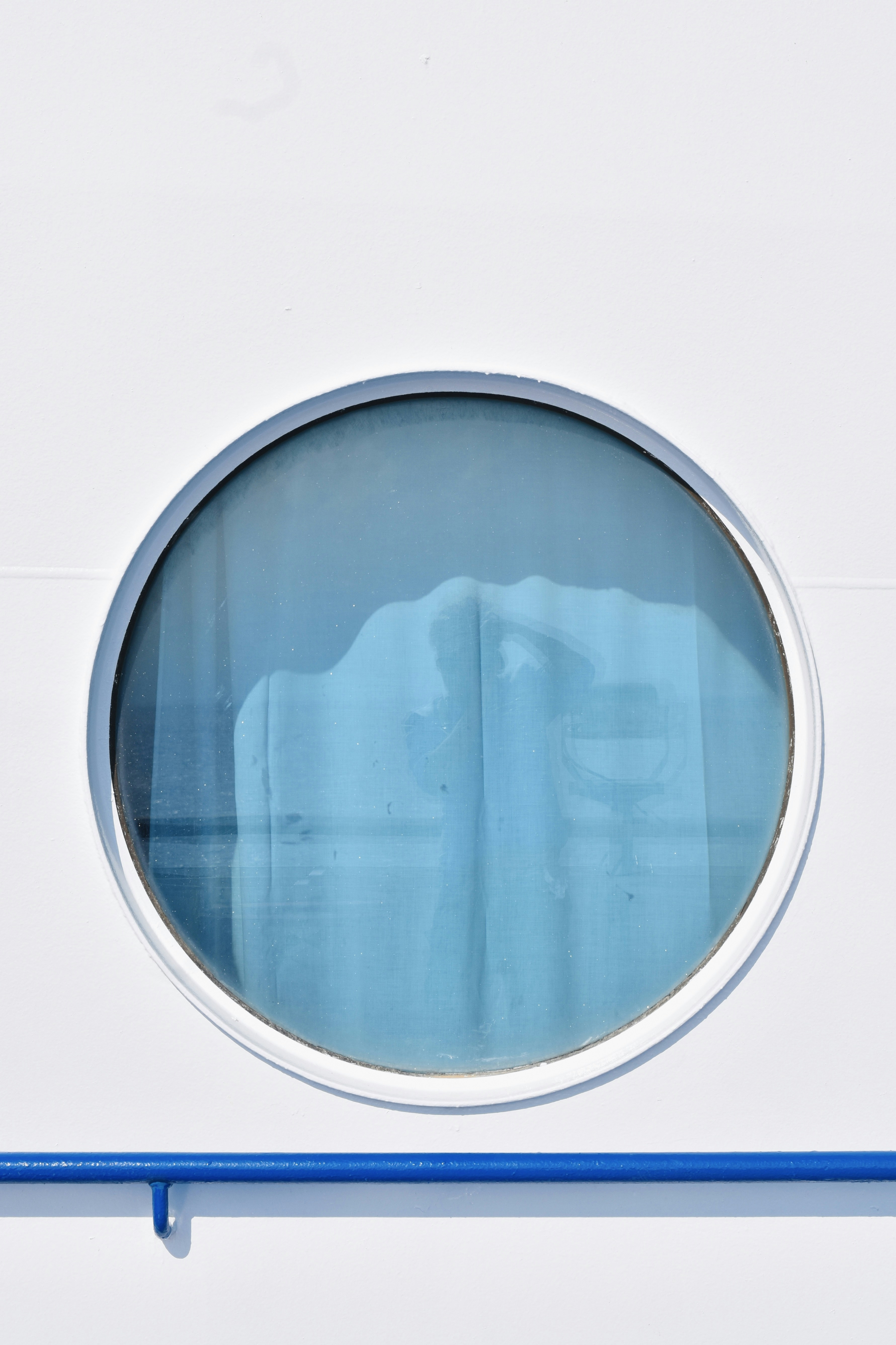 Blue Circular Window: A Quiet Moment on a White Vessel